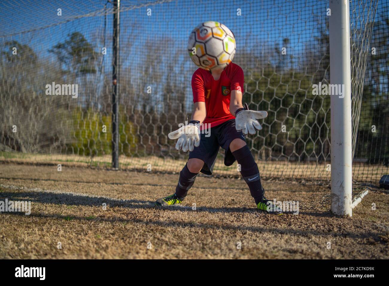 Closeup shot of boy goalkeeper performing a save while playing soccer ...