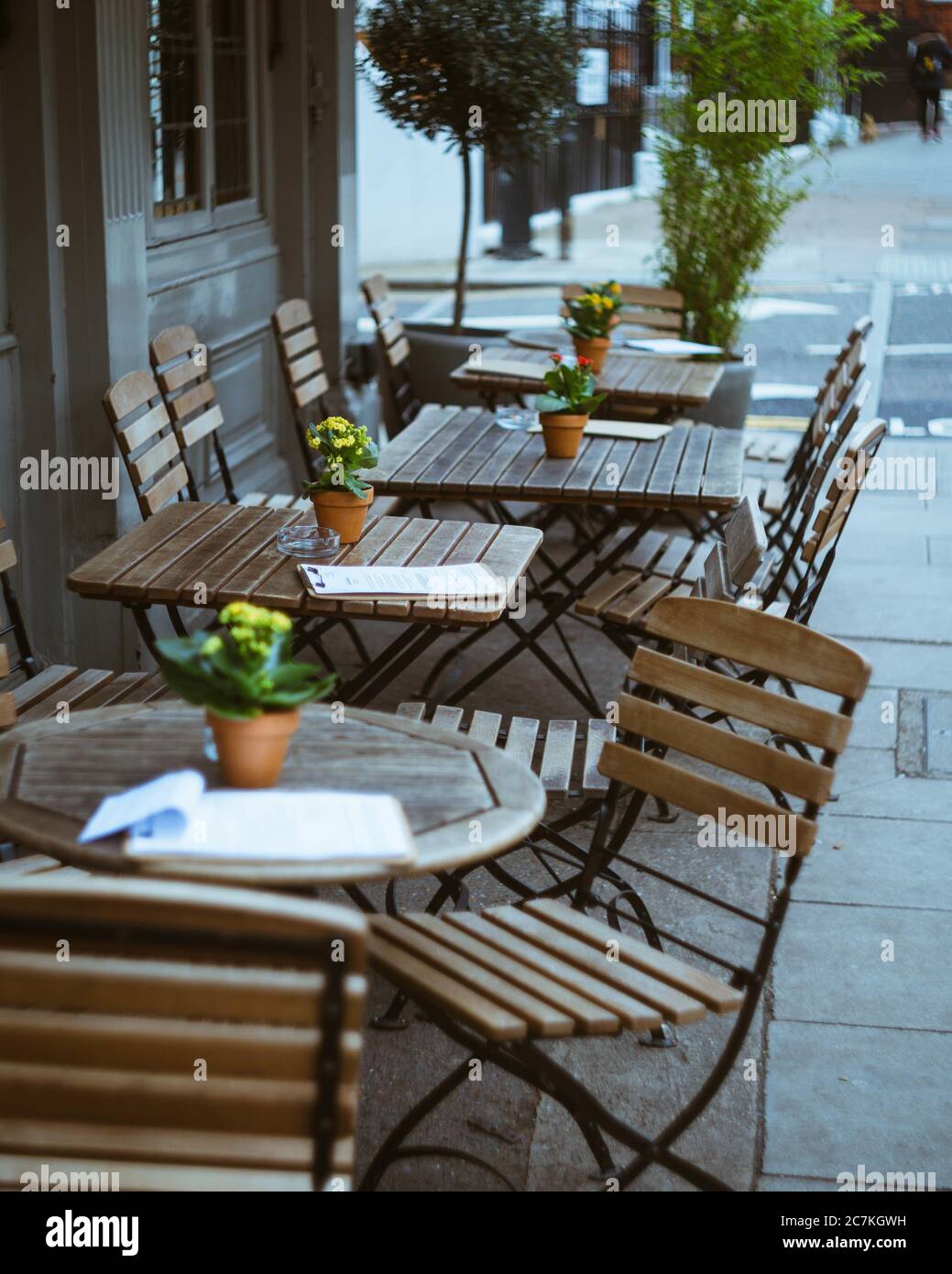 Outdoor cafe with wooden chairs and tables surrounded by buildings ...