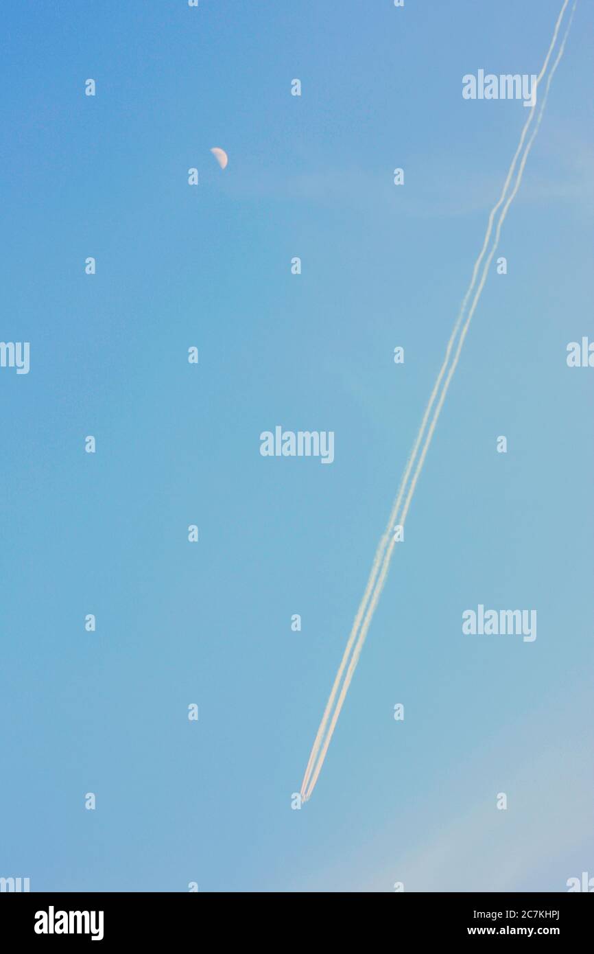 Vertical shot of the blue beautiful sky with airplane engine trails and ...