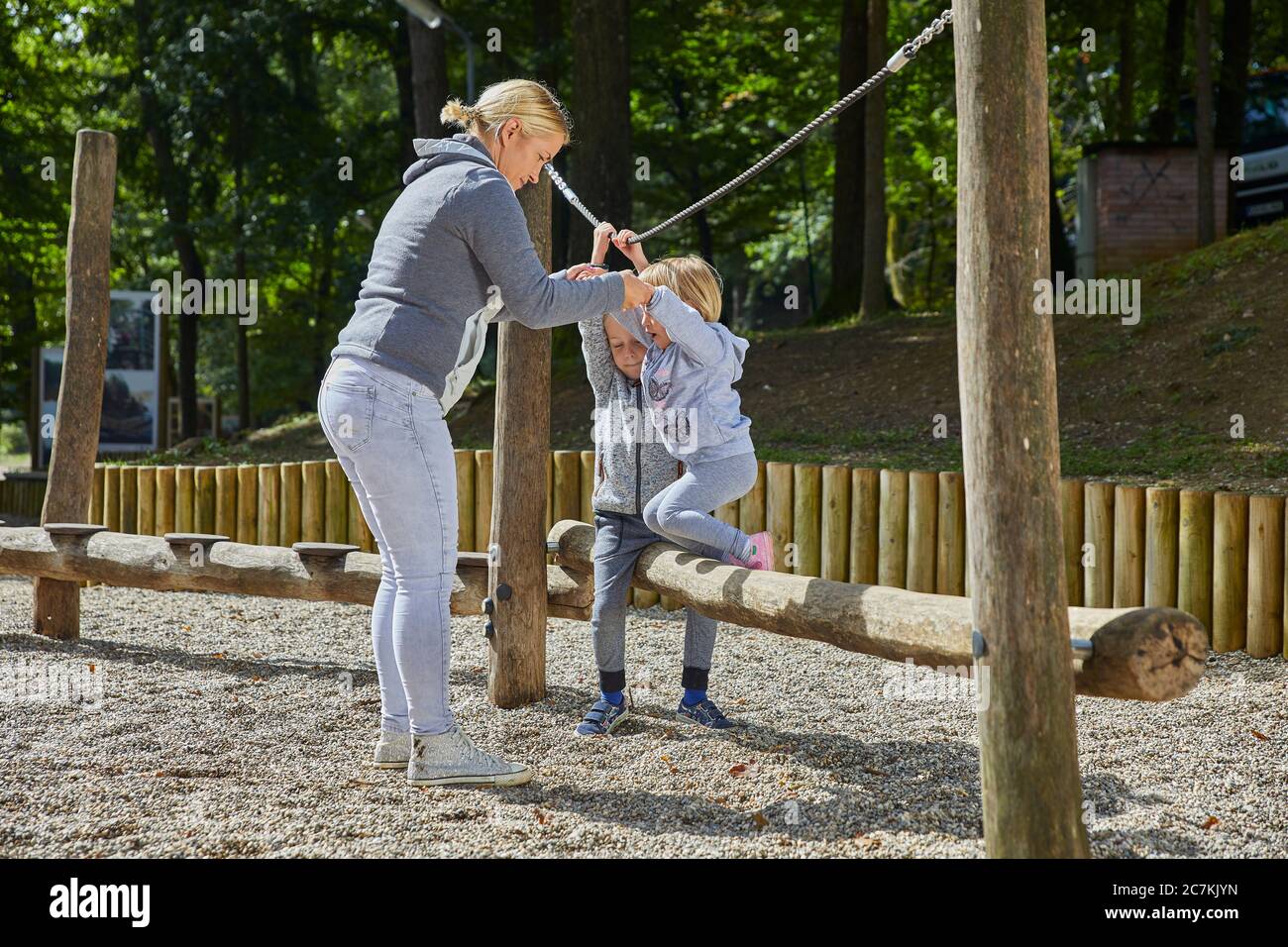 Little girl hanging on the rope in the playground under the supervision ...