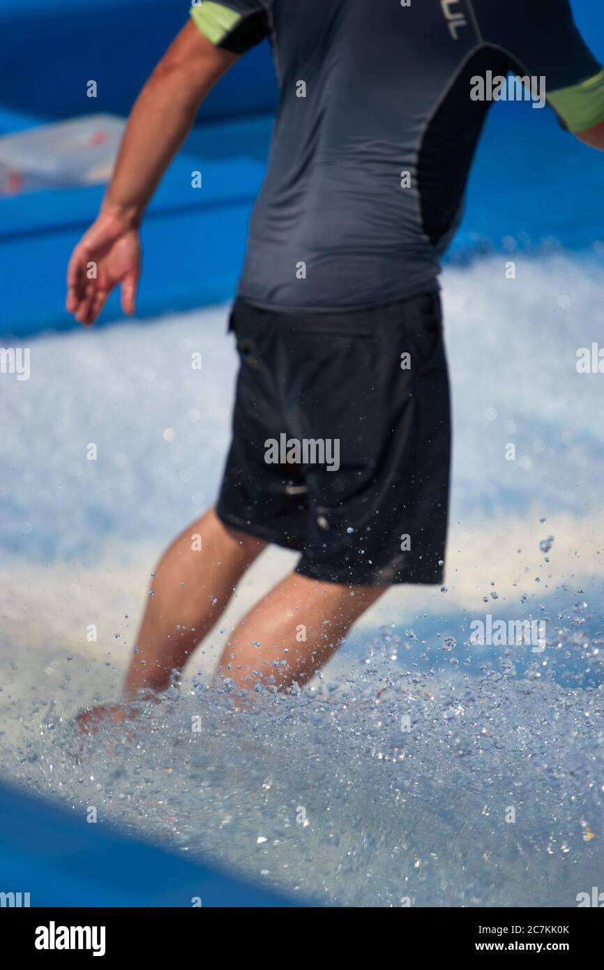 Vertical close up shot of a man riding the flow rider wave machine on ...