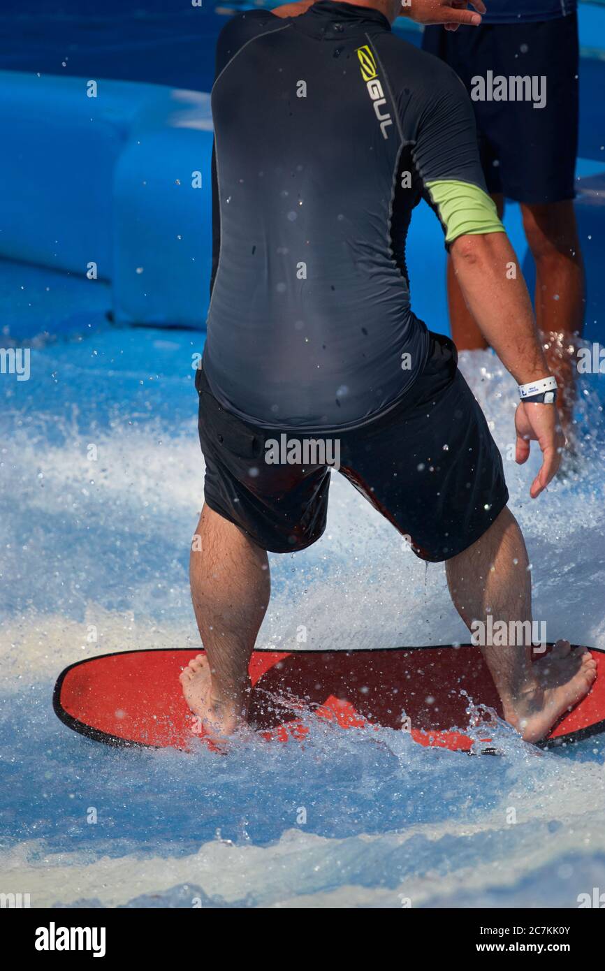 verticalshot of a man riding the flow rider wave machine on top of a ...