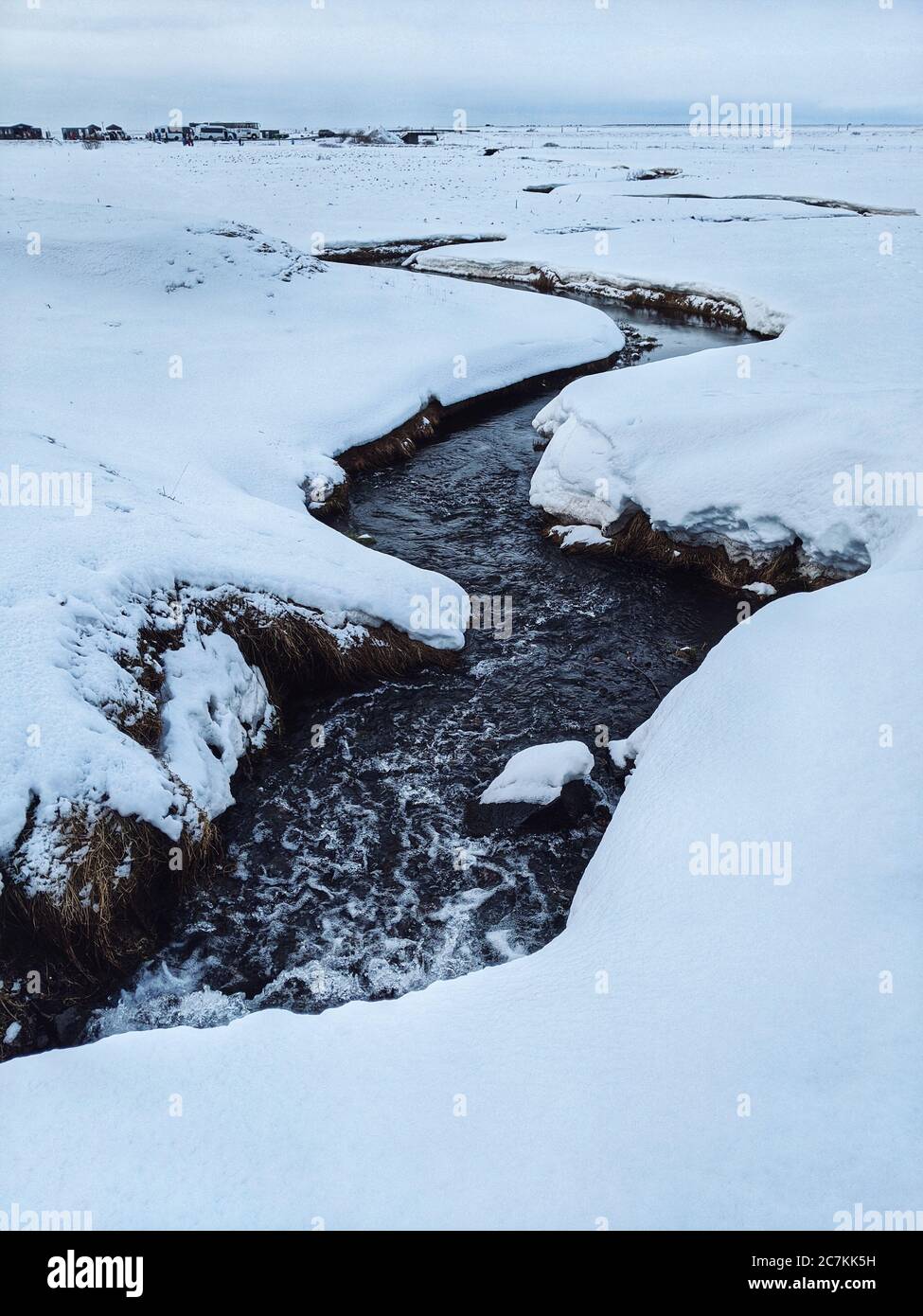 Stream meanders through the snowy Icelandic landscape, near ...