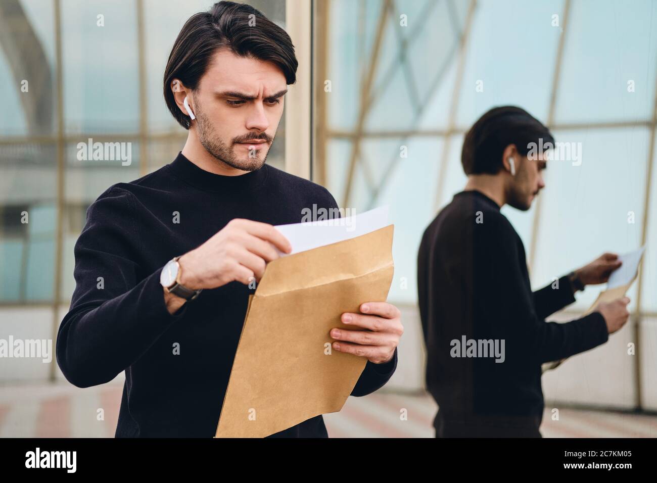Portrait of young serious man angrily reading envelope with response ...