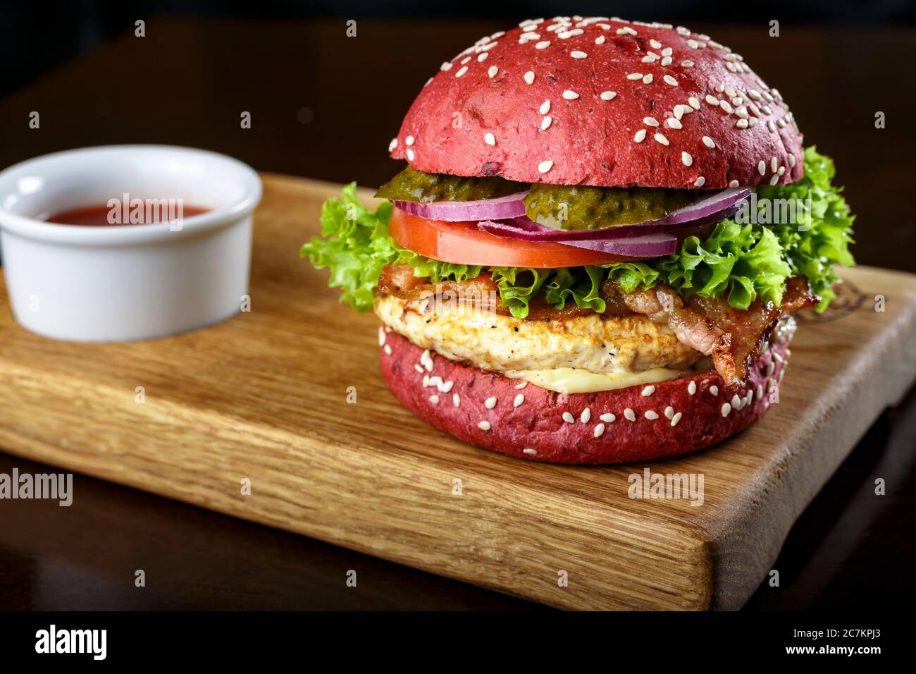 red burger with cutlet and vegetables on a cutting wooden board. place ...