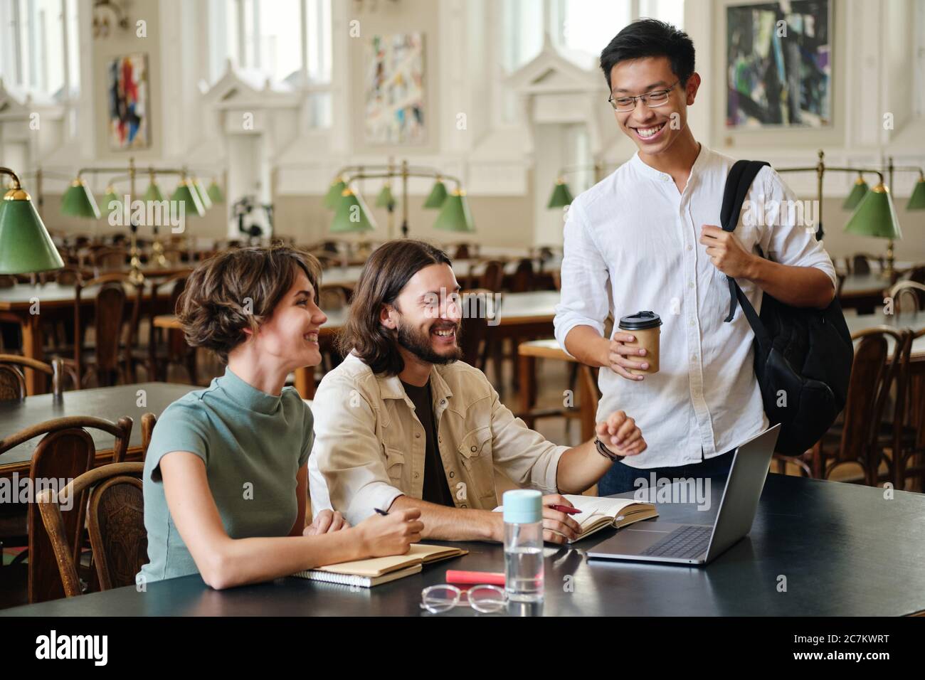 Group of young cheerful students joyfully talking while studying ...