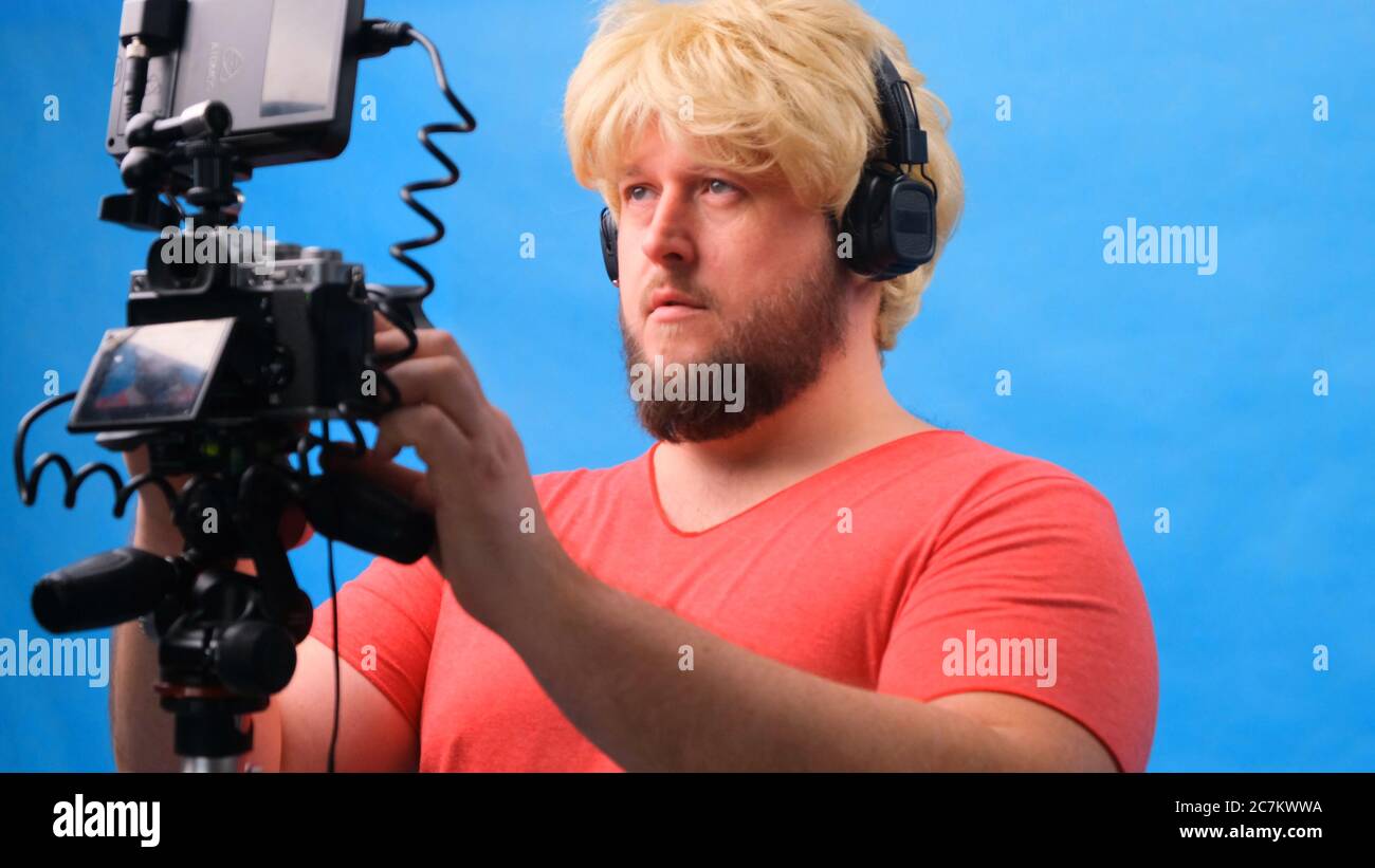 freaky fat man in a wig and a pink t-shirt makes a video blog against a ...