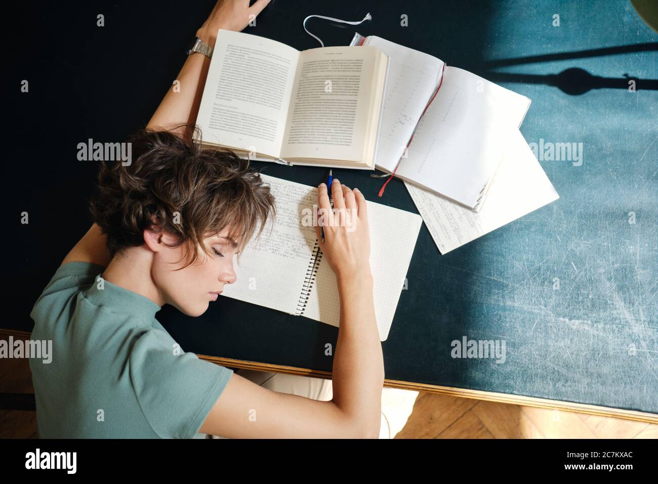 Top view of young exhausted female student tiredly sleeping on desk ...