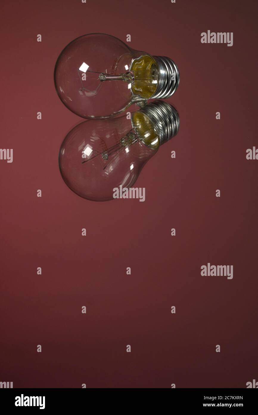 An old incandescent light bulb on red background Stock Photo - Alamy