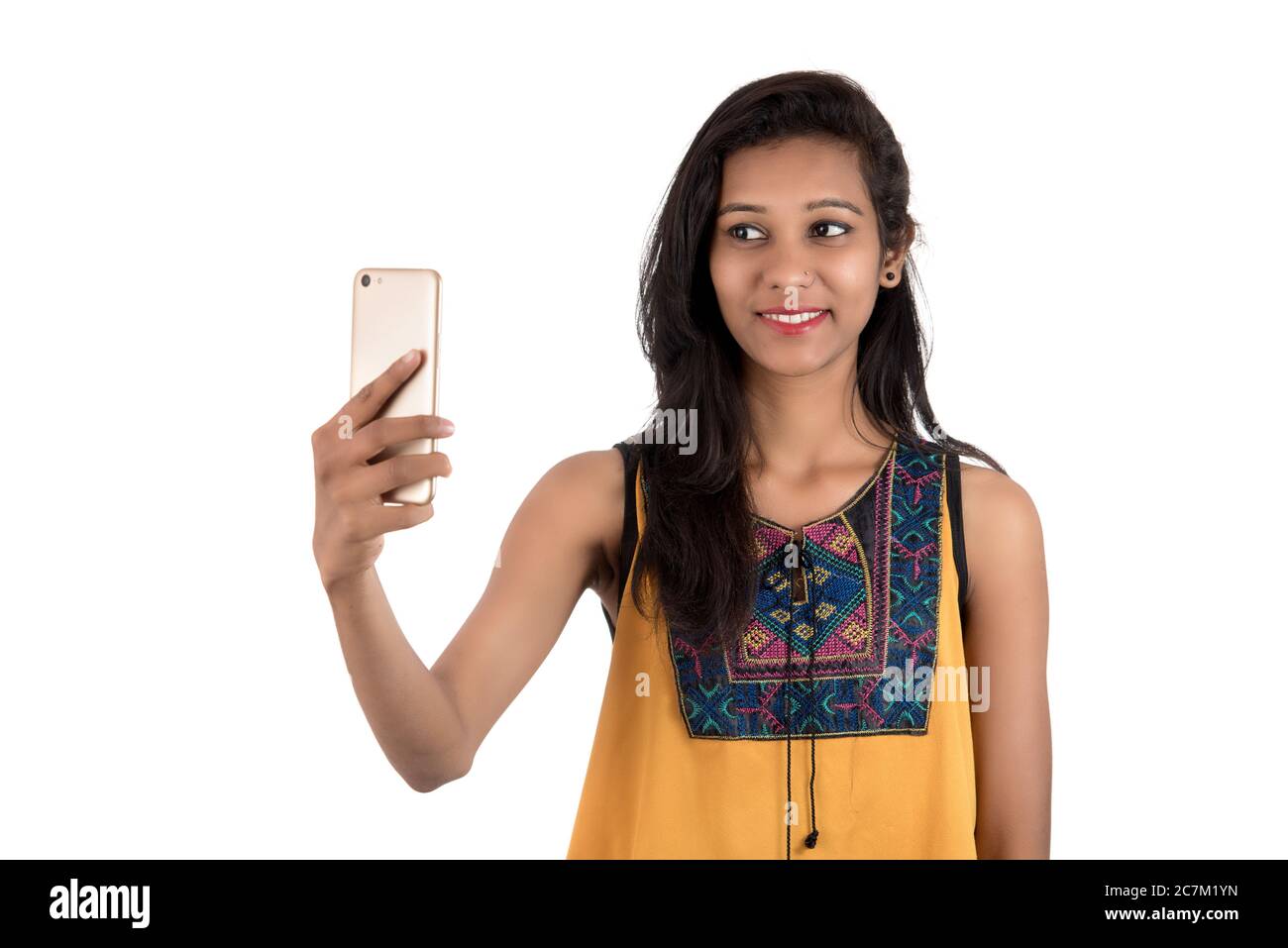 Portrait of a happy young girl using mobile phone isolated over white ...