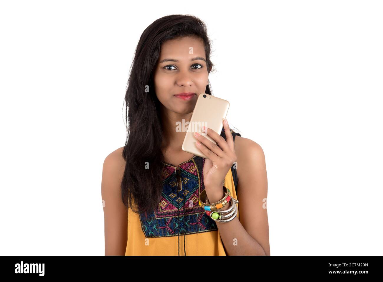 Portrait of a happy young girl using mobile phone isolated over white ...