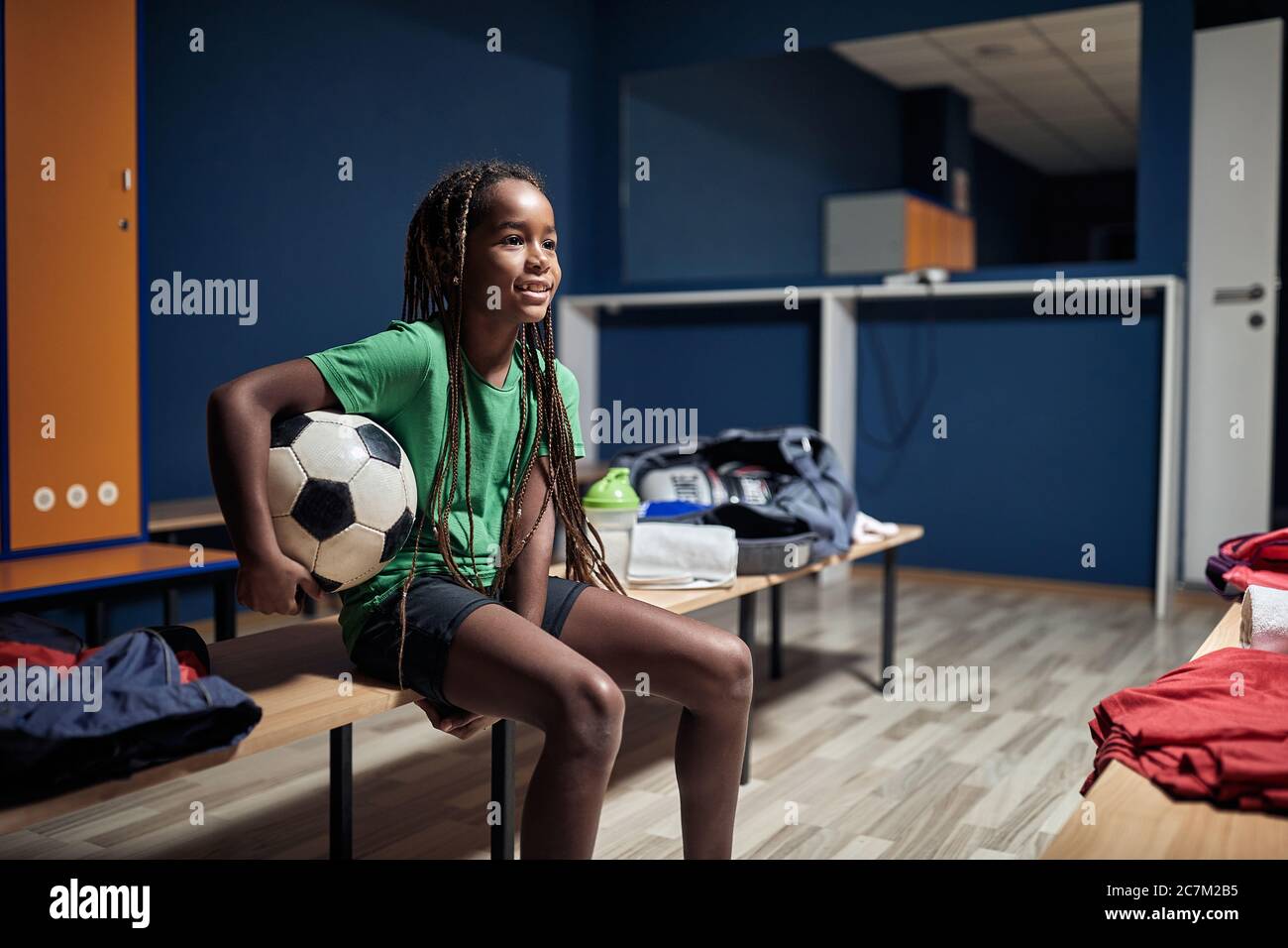 Soccer player preparing for game in locker room.Child girl with soccer ...