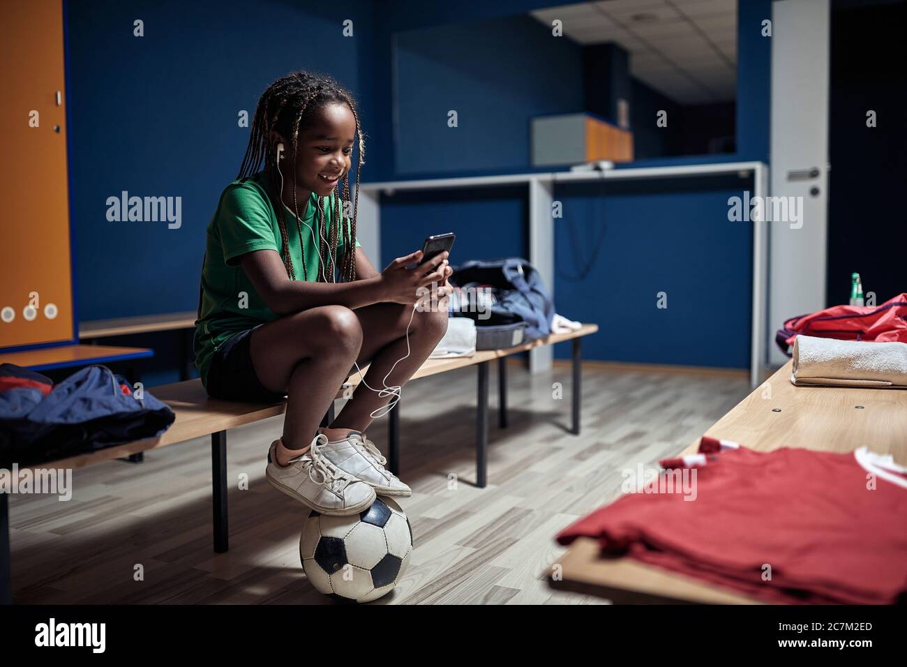 Soccer player before training listen music on phone. Child girl listen ...