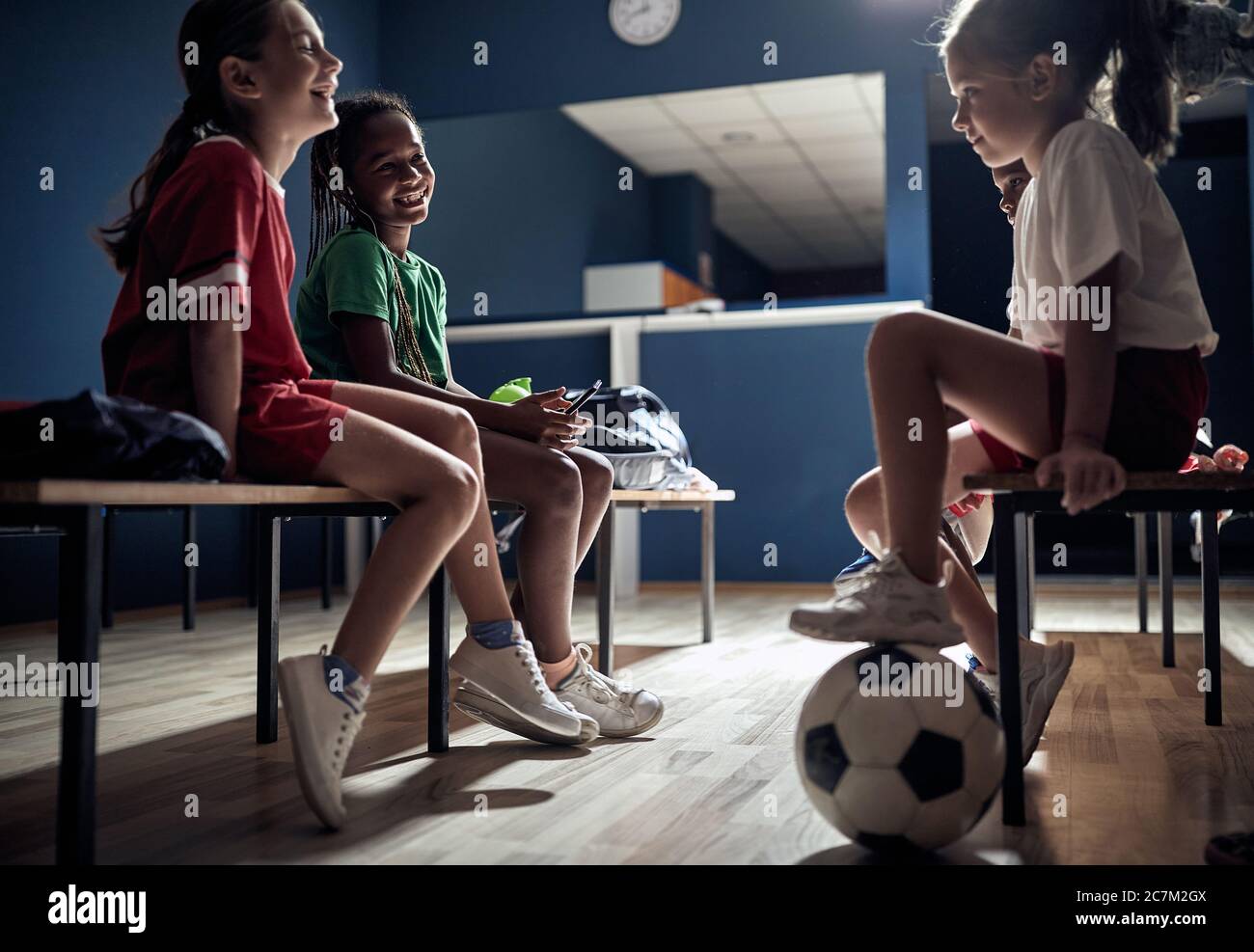 Child girl with soccer ball in changing room.Smiling girls sitting in a ...