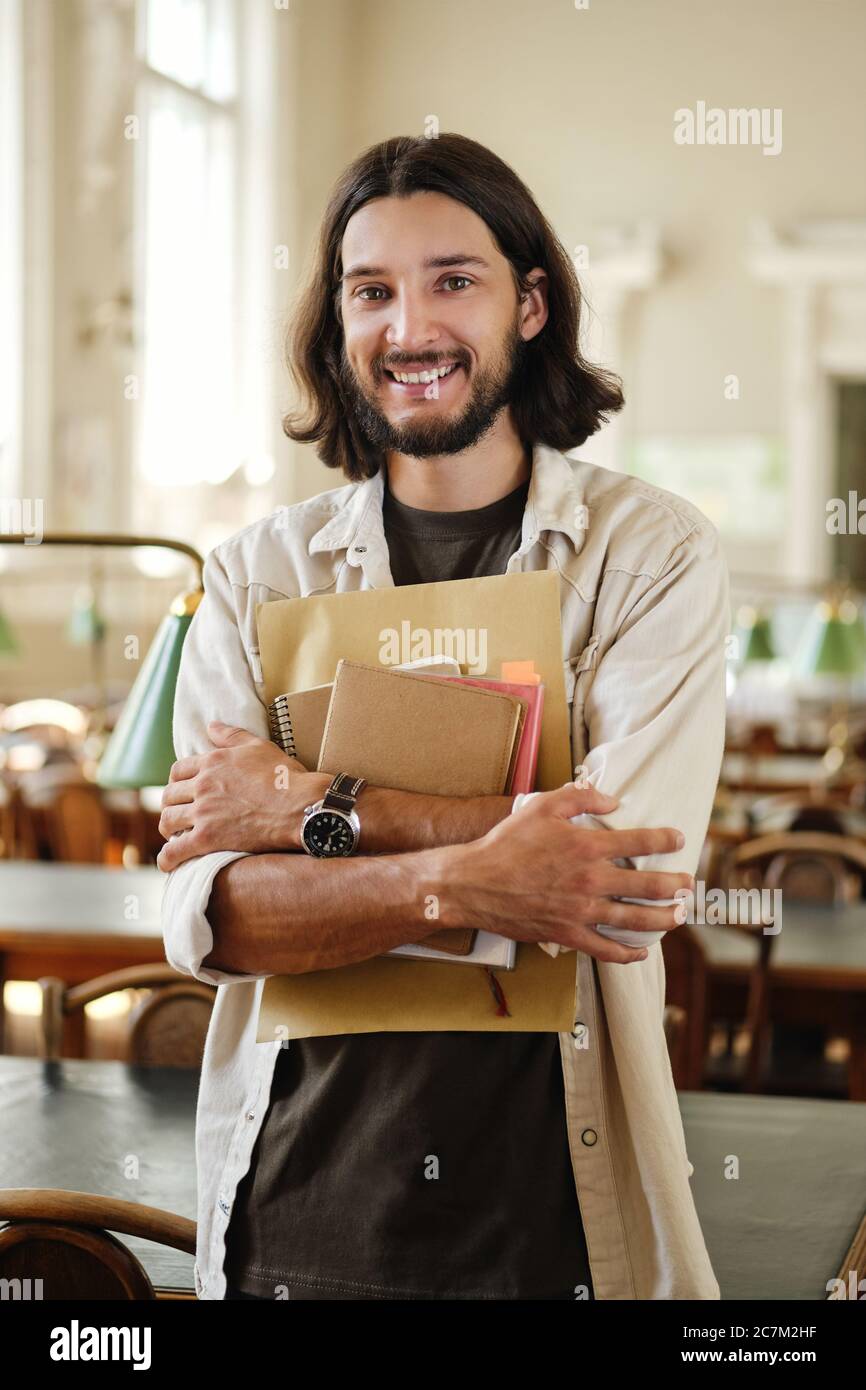 Portrait of young handsome male student with notepad and book happily ...
