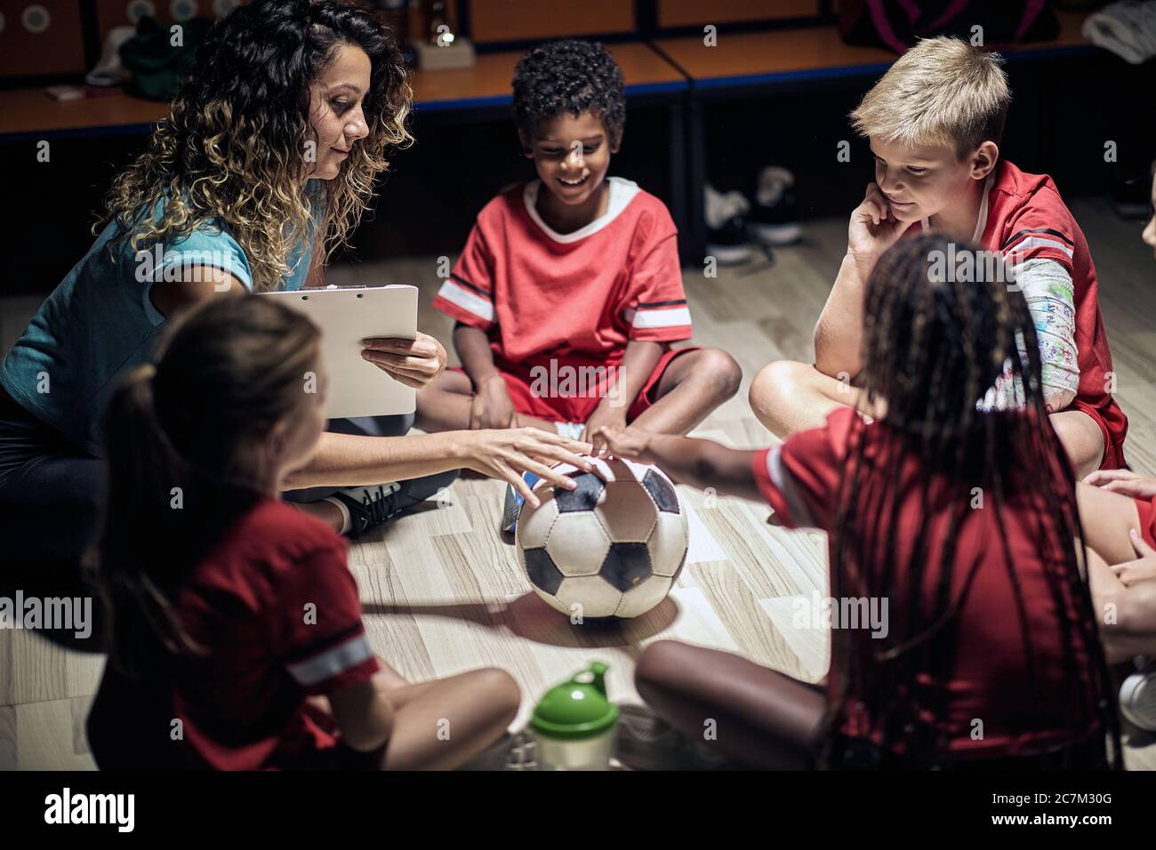 Woman Coach In Circle In Locker Room With Her Pupil Soccer Sport Team