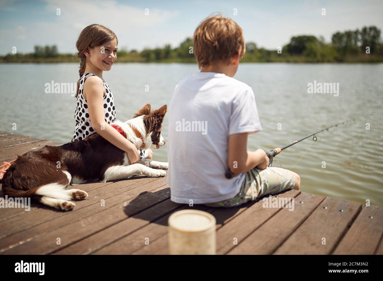 Happy children having fun at summer vacation and fishing in a pond ...