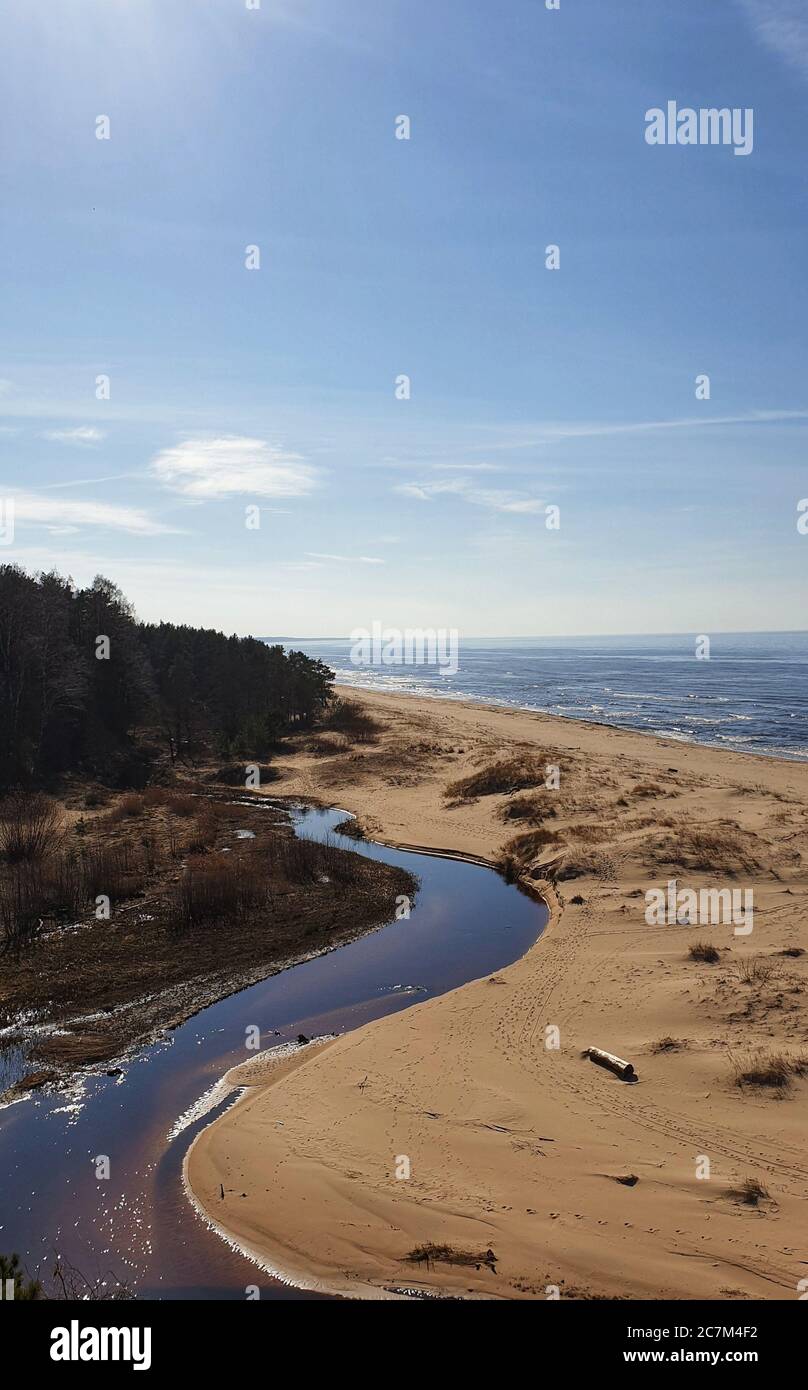 Vertical shot of a sandy shore by the sea surrounded with mountains ...