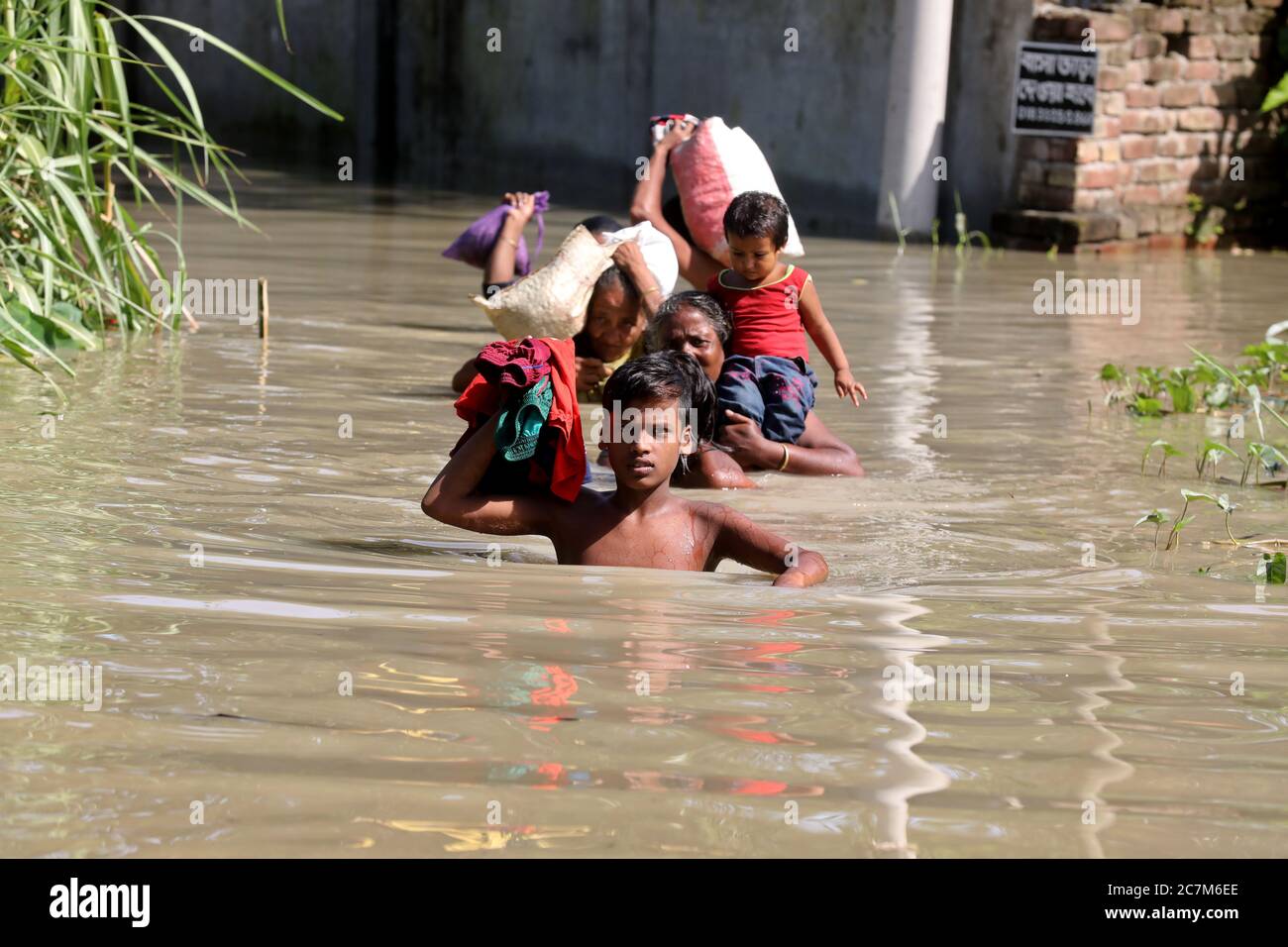 Dhaka, Bangladesh - July 17, 2020: A family is wading through chest ...