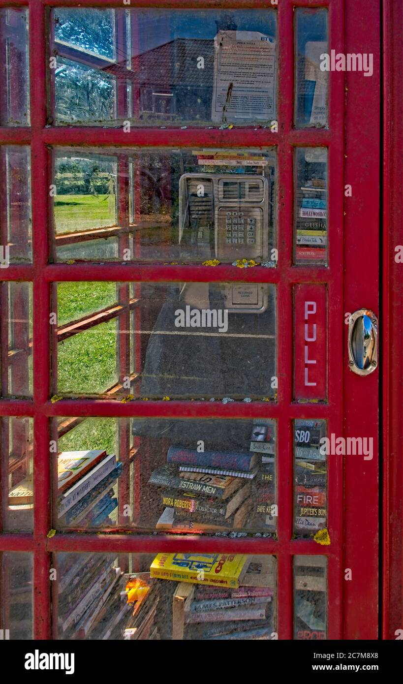 Disused Norfolk village red BT phone box used as a library. Door closed ...