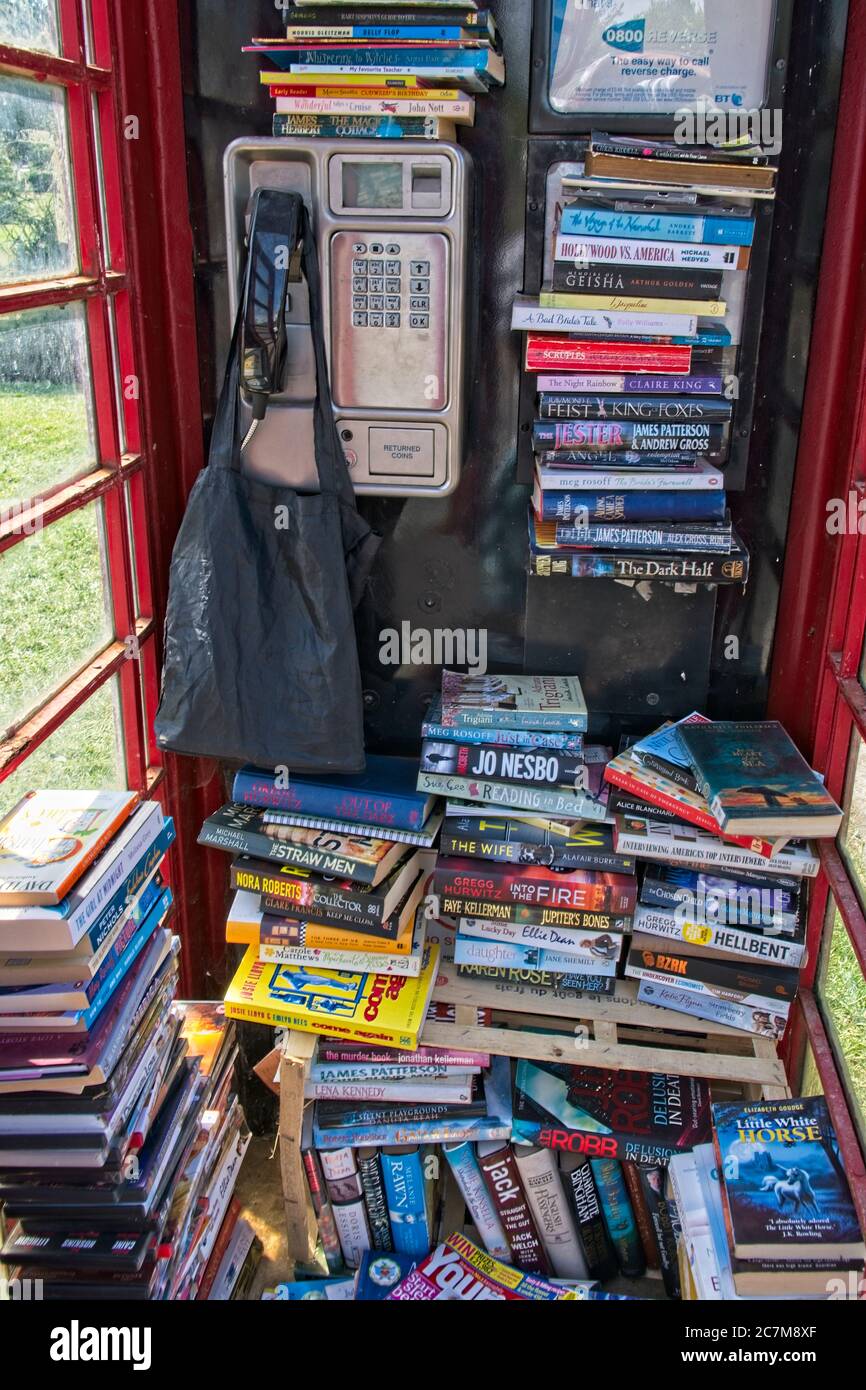 Disused Norfolk village red BT phone box used as a library. Door open ...