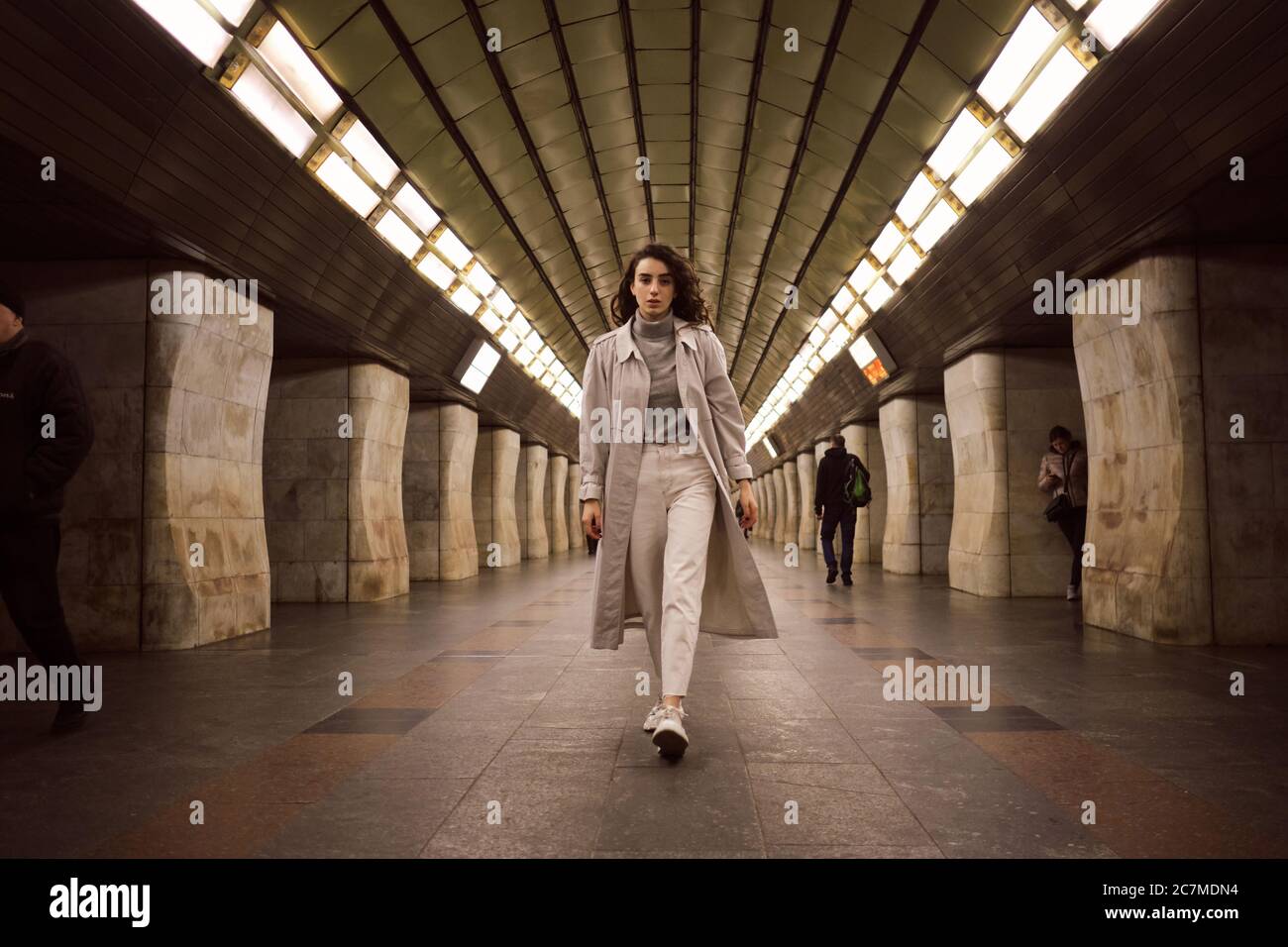 Attractive girl in trench coat confidently walking through subway ...