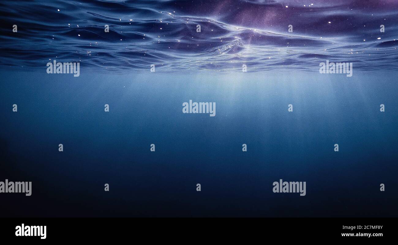Dark blue ocean surface view from underwater with the rays of sunlight ...