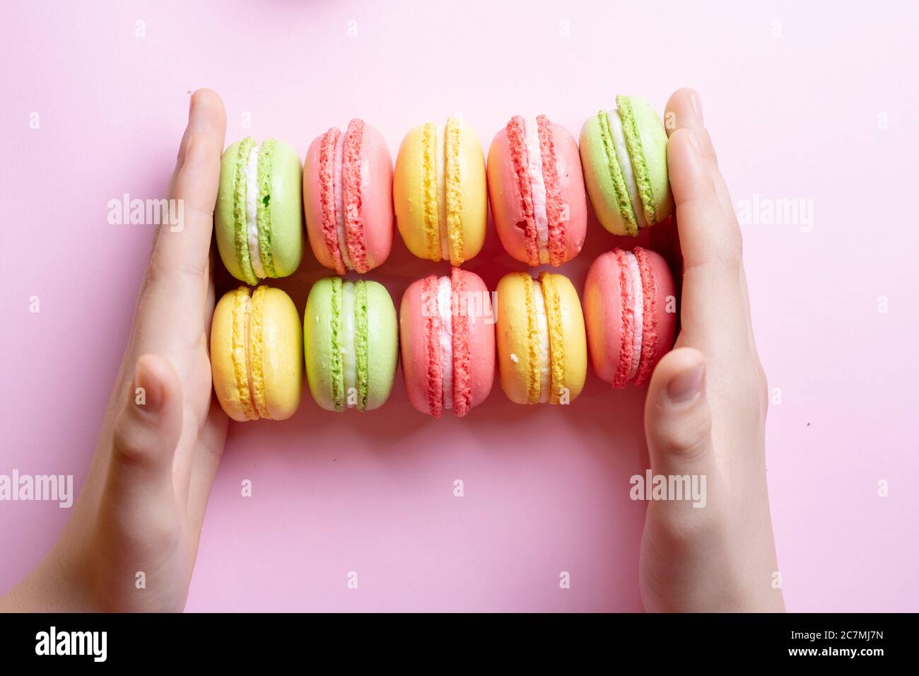 Girl holding ten colorful French macarons in hands, top view Stock ...