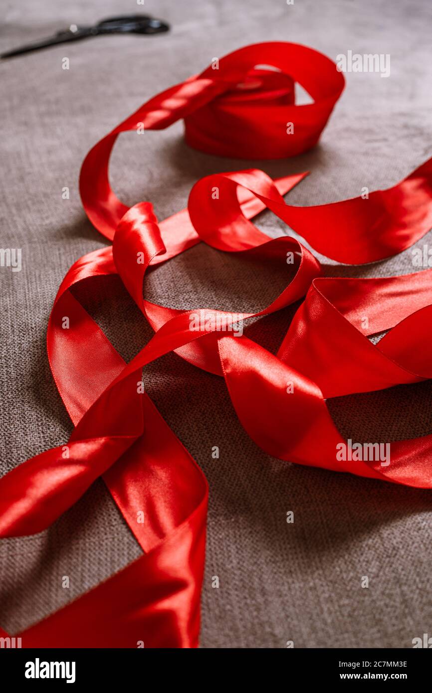 red ribbon with a bobbin unwound needlework Stock Photo - Alamy