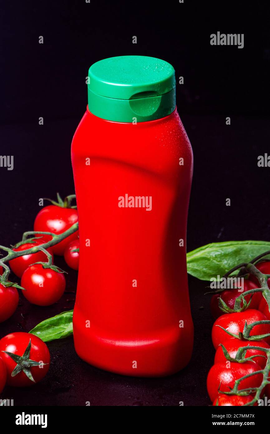 bottle, tube of red ketchup with a green cap and two ripe branches of ...