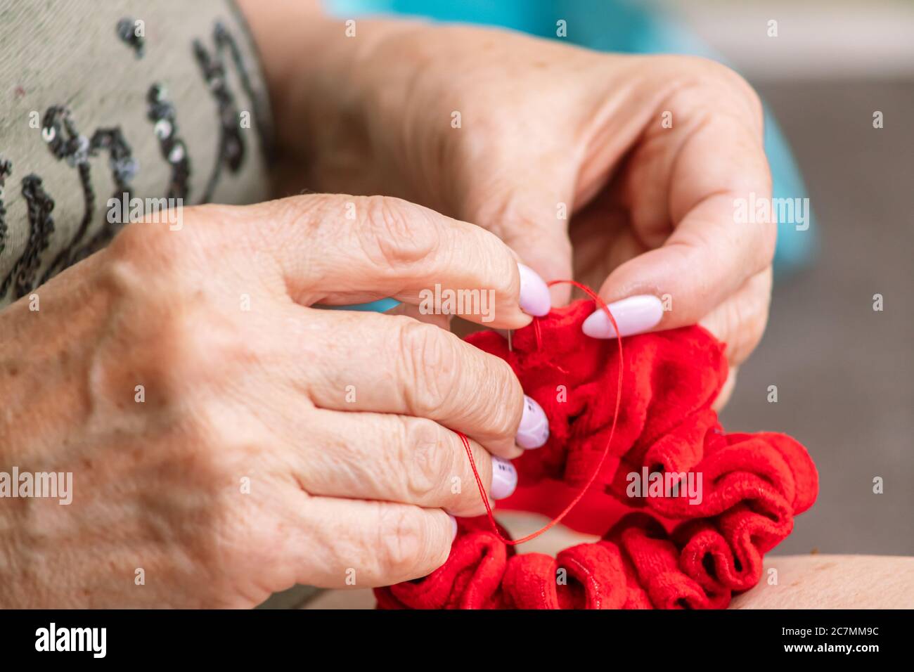 old female hands sew a red cloth up needle with a needle Stock Photo ...