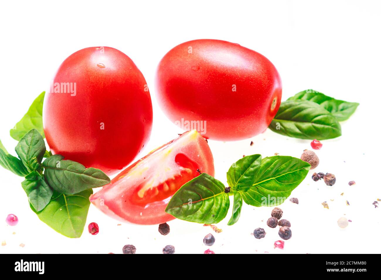 tomatoes with green basil leaves and dry pepper on a white background ...