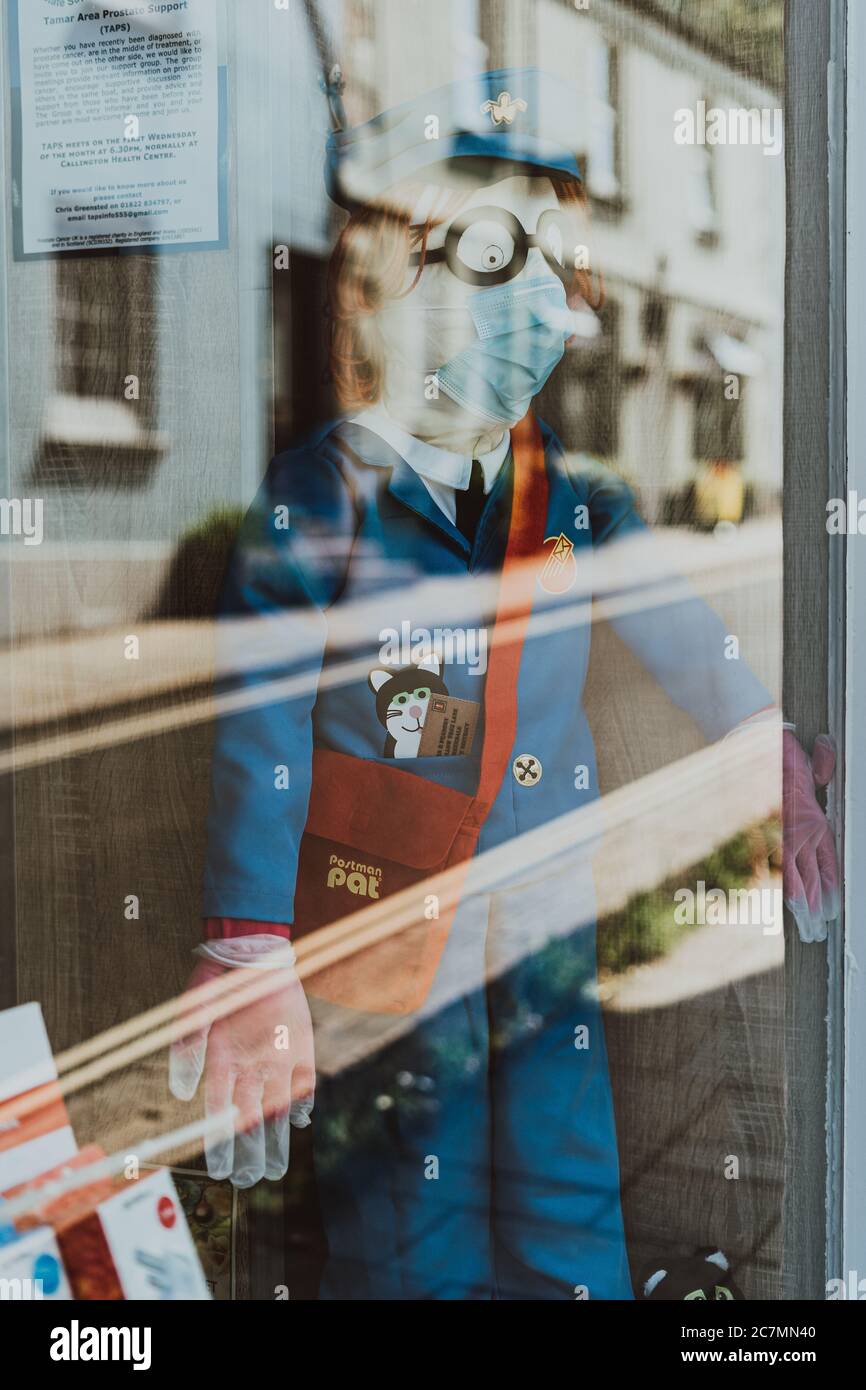 Postman in post office shop window - covid-19 Stock Photo - Alamy