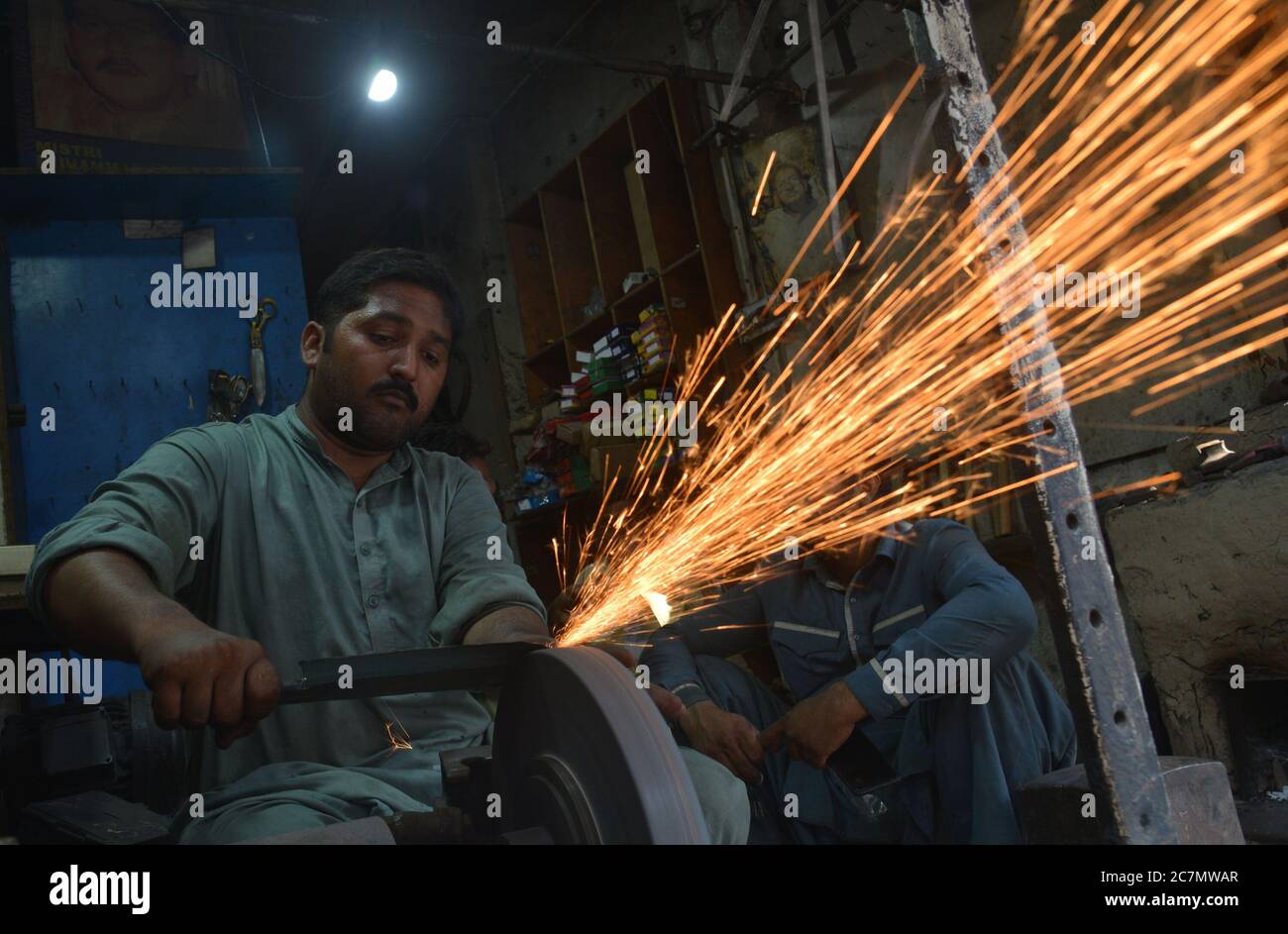 Pakistani blacksmiths sharpens meat cleavers various tools and knives ...