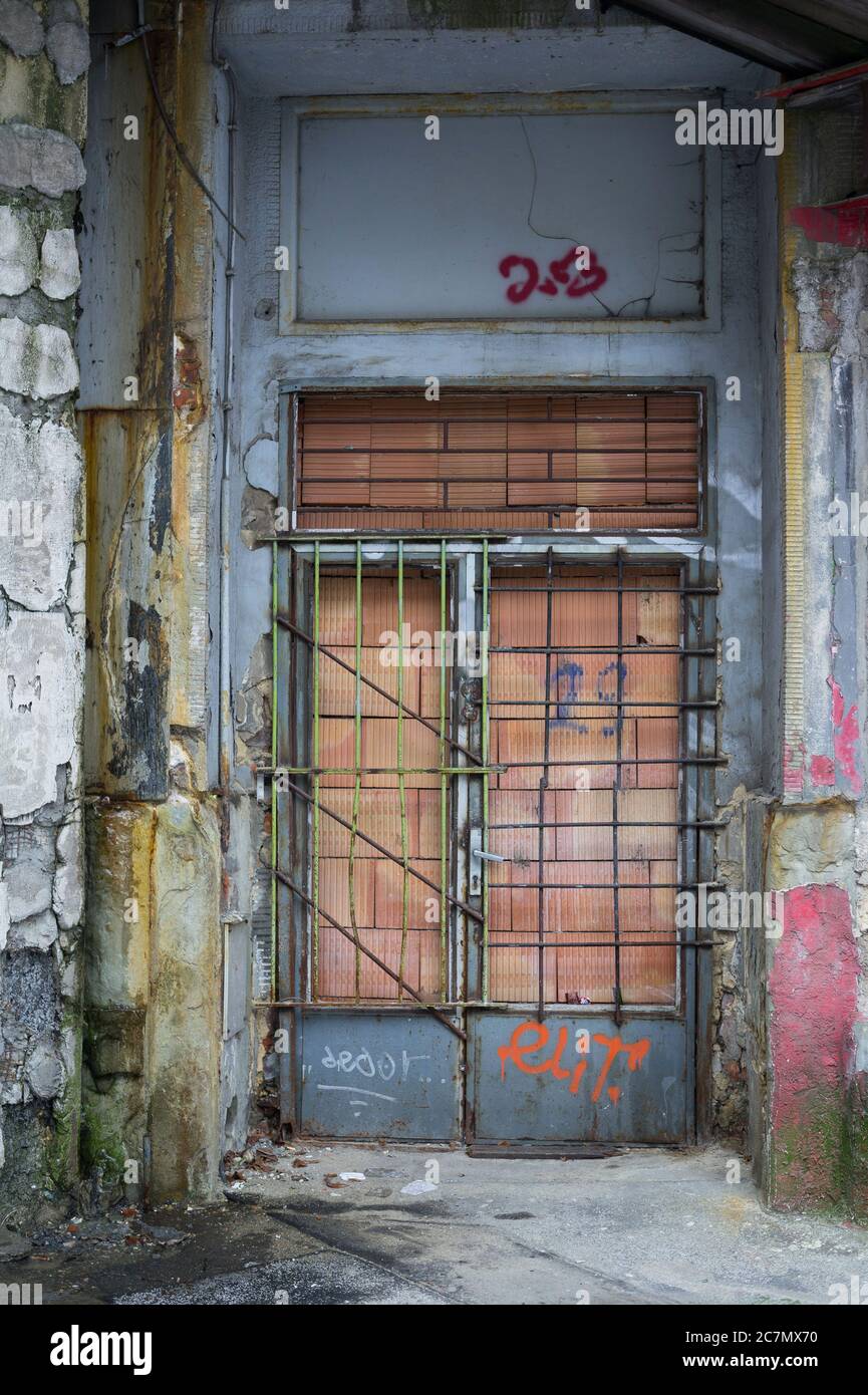 Ugly aged door. Forbidden entrance to the building is closed by bricks ...