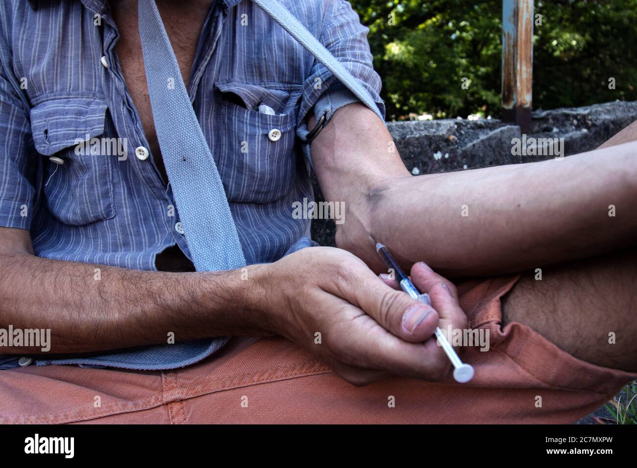 Hands of a drug addict with a syringe full of narcotic, heroin or ...