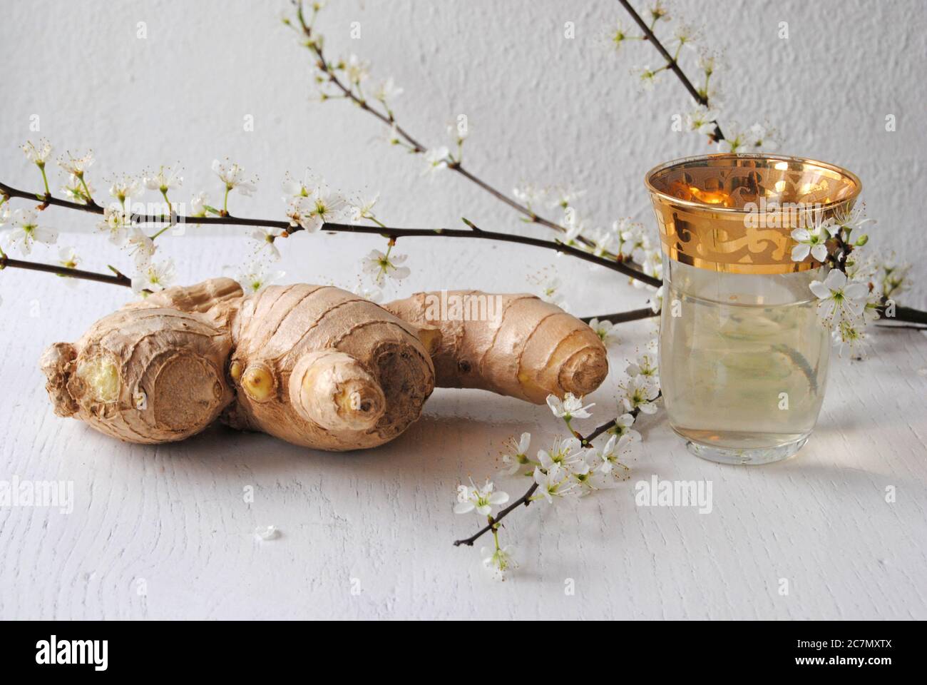 Closeup shot of white ginger roots near a glass cup and a branch with ...