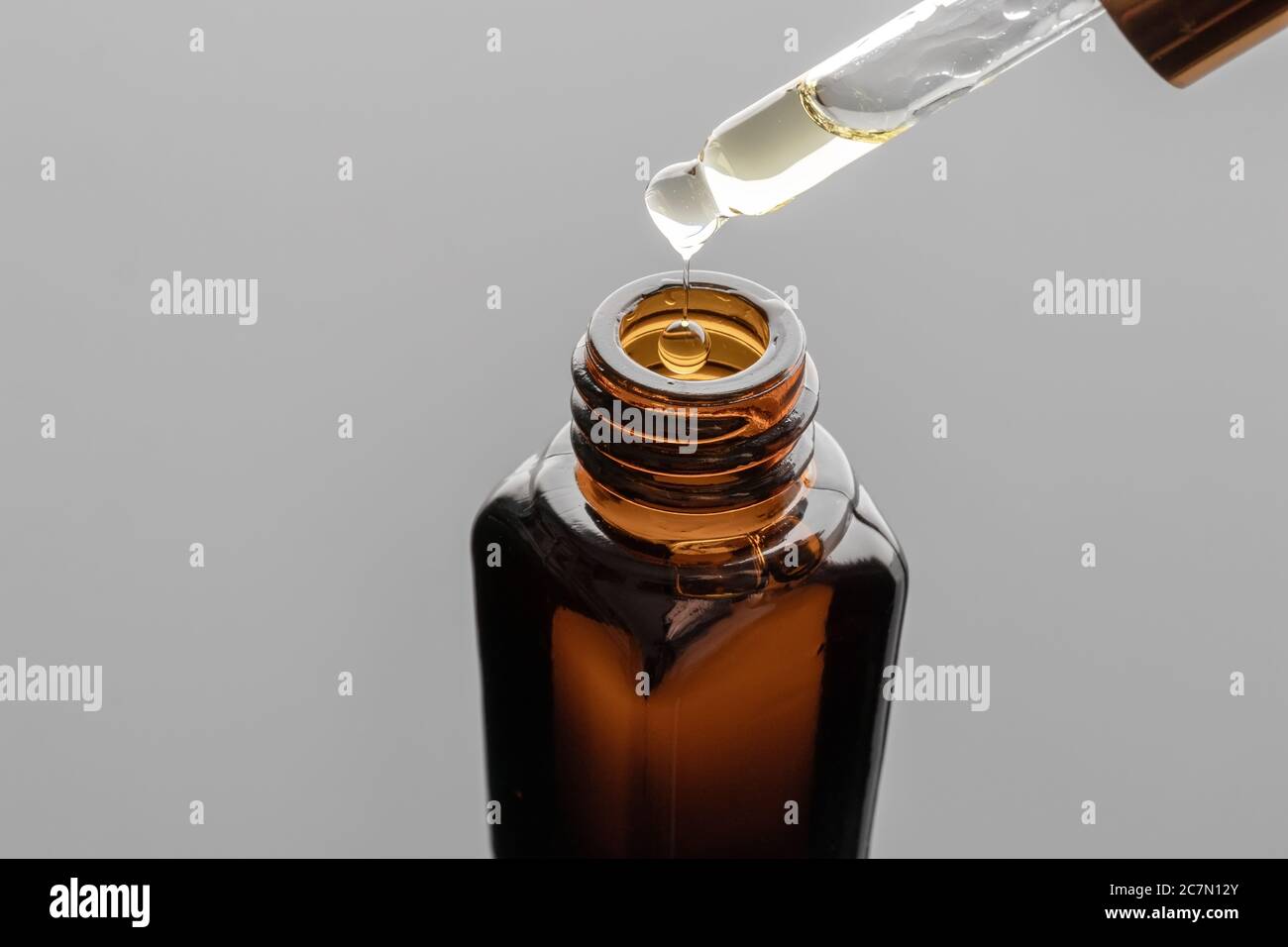 A drop of essential oil falling into a brown bottle Stock Photo - Alamy