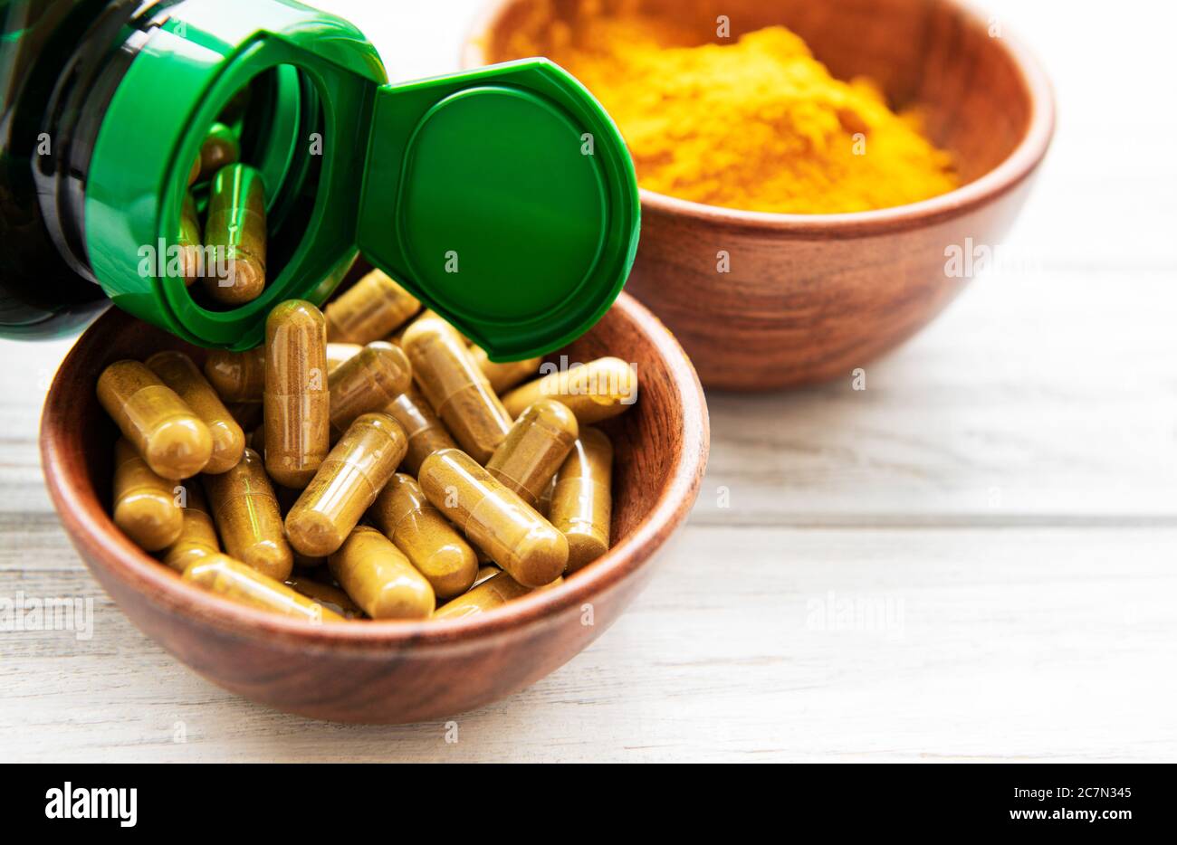 Turmeric powder and turmeric capsules on white wooden background Stock ...