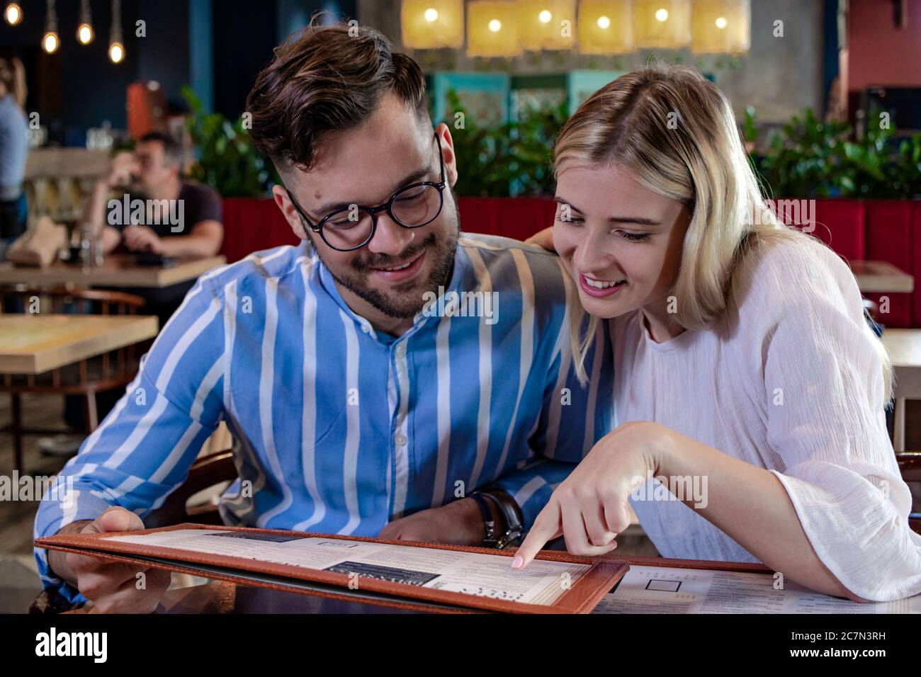 Happy young romantic couple choosing food from menu at dinner in a ...