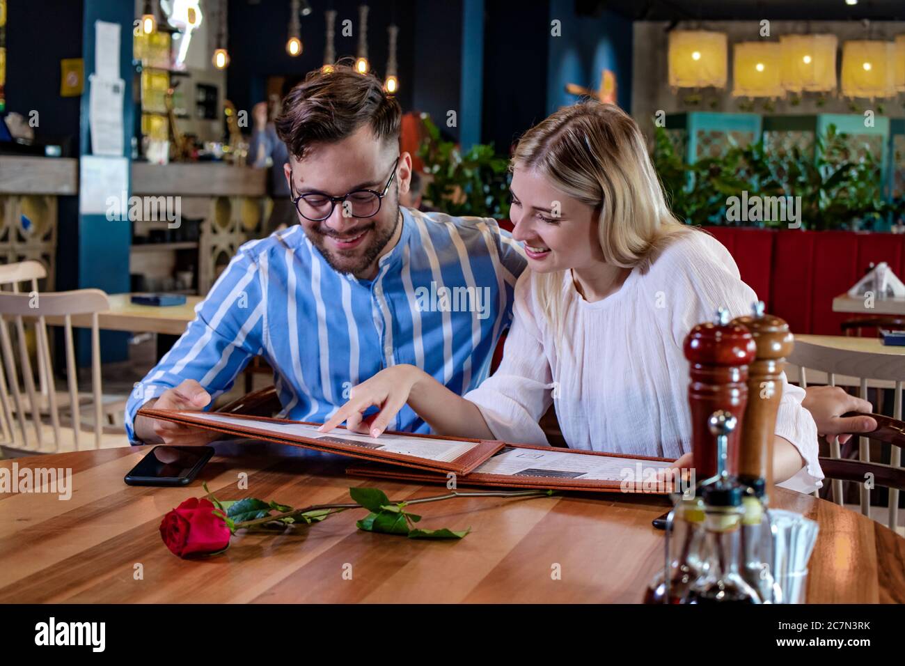Happy young romantic couple choosing food from menu at dinner in a ...