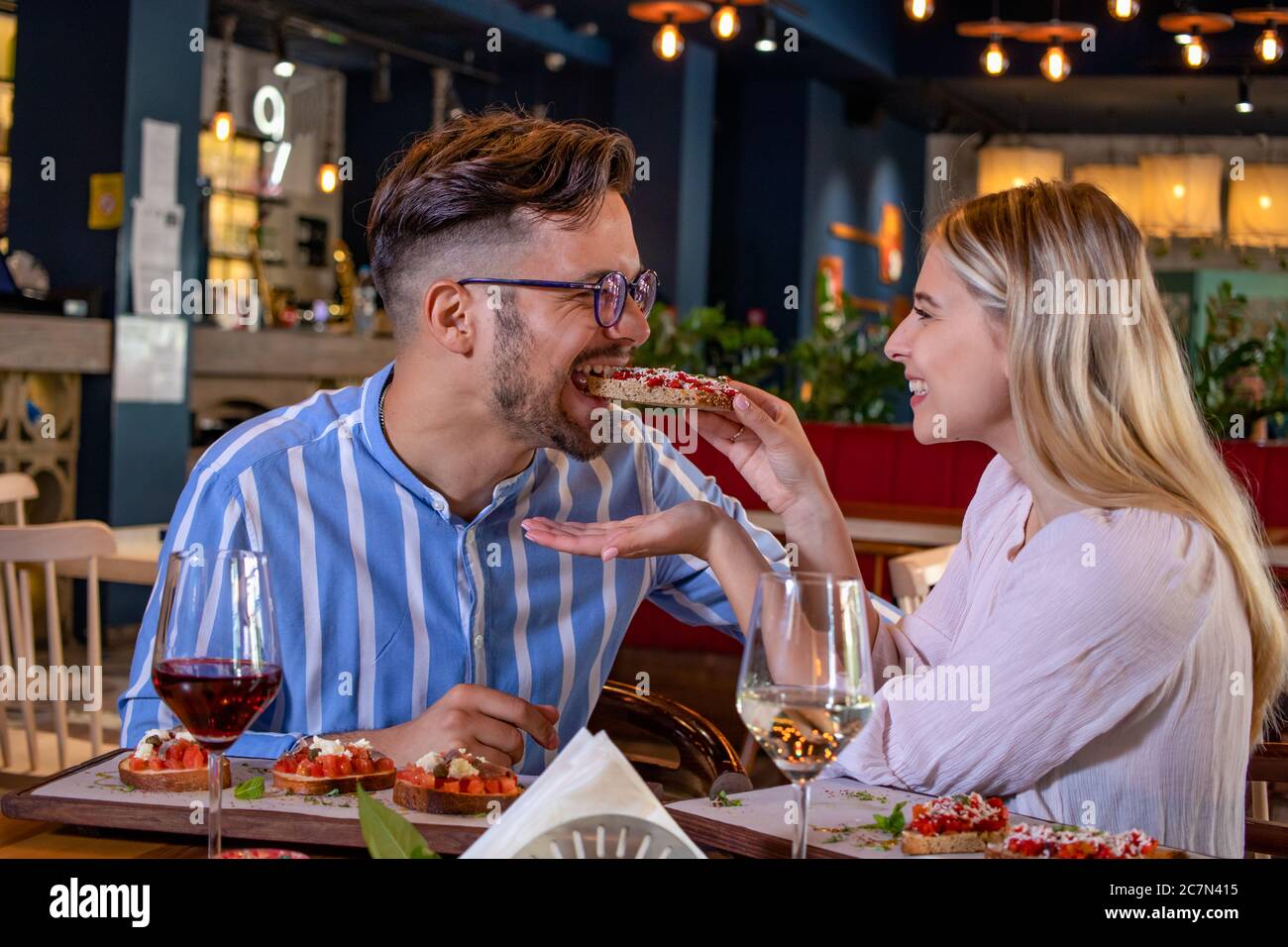 Happy young romantic couple in love feeding each other with bruschetta ...