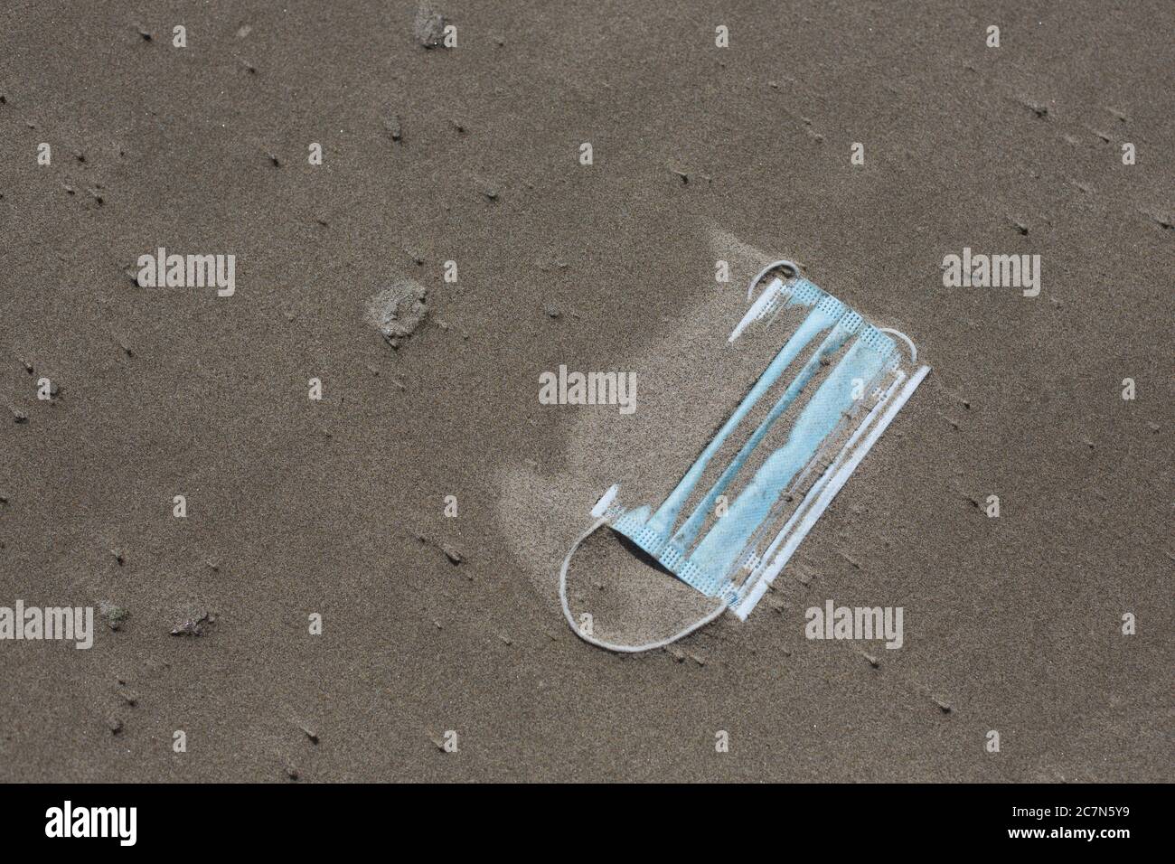 A disposable surgical mask in sand on a beach Stock Photo - Alamy