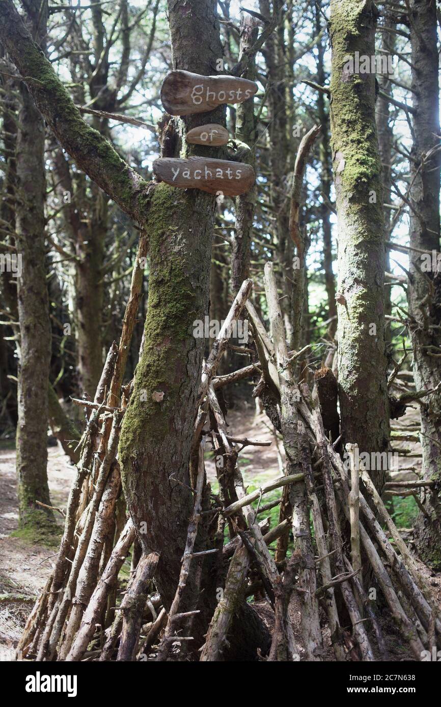 A child's fort made of sticks under a tree with signs reading "Ghosts ...
