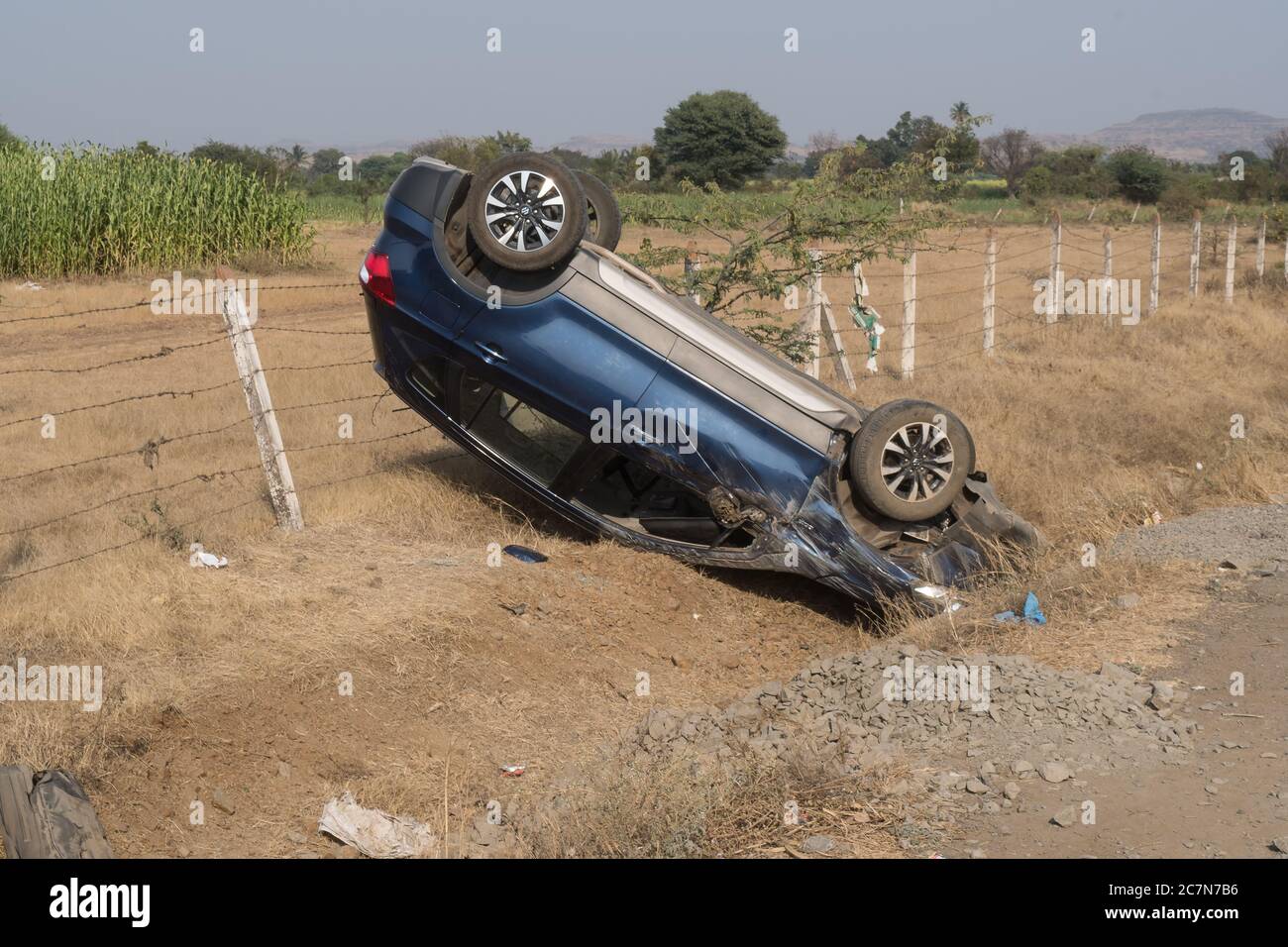 Photo of a car that is crashed and flipped before falling on a roadside ...