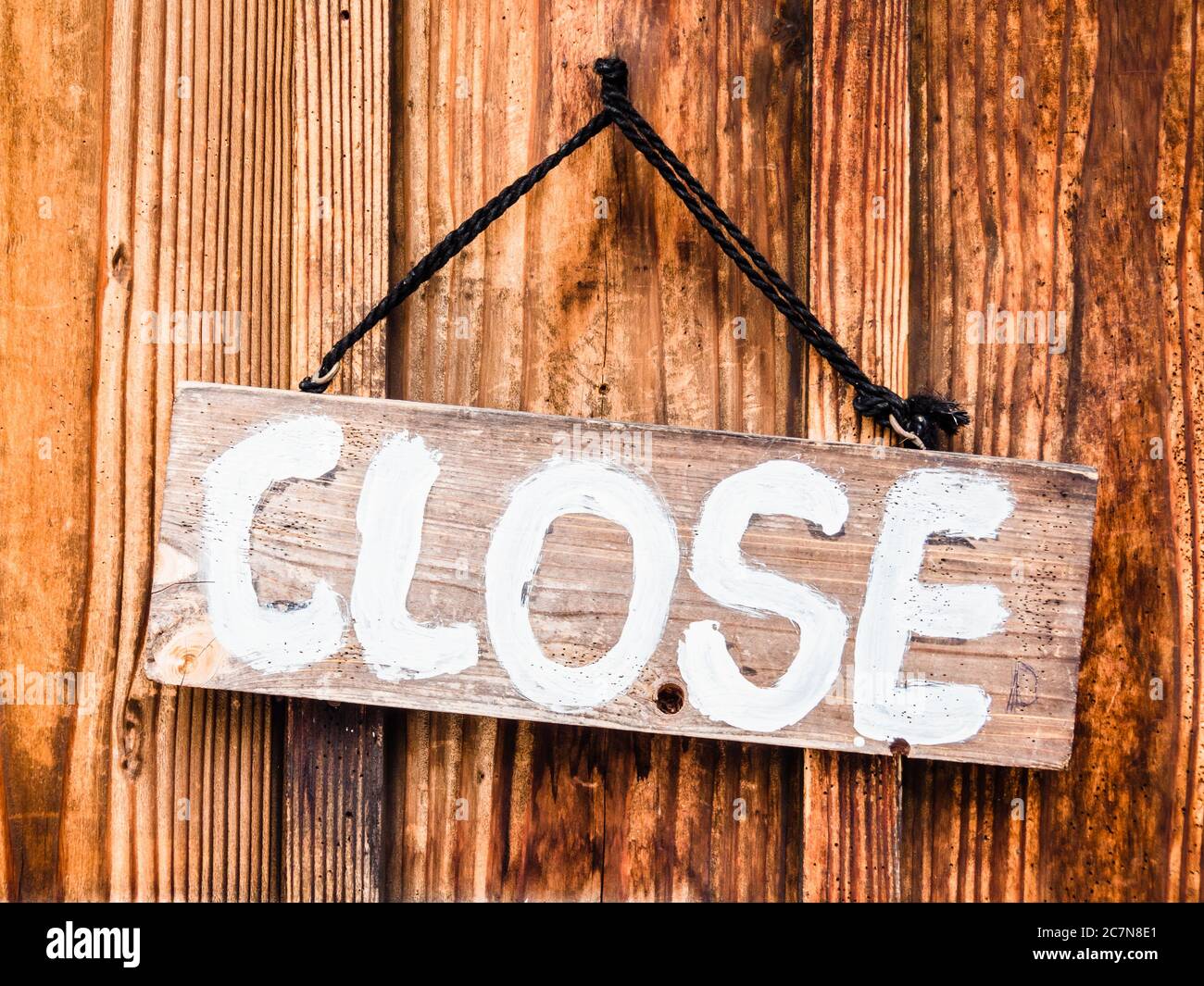 Wooden sign with [CLOSE] written on it hanging with ropes from the door ...