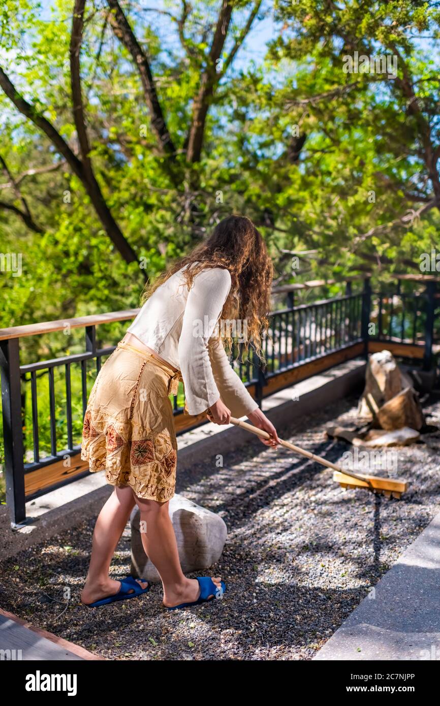 Outdoor zen rock garden outside in Japan with woman holding rake raking ...