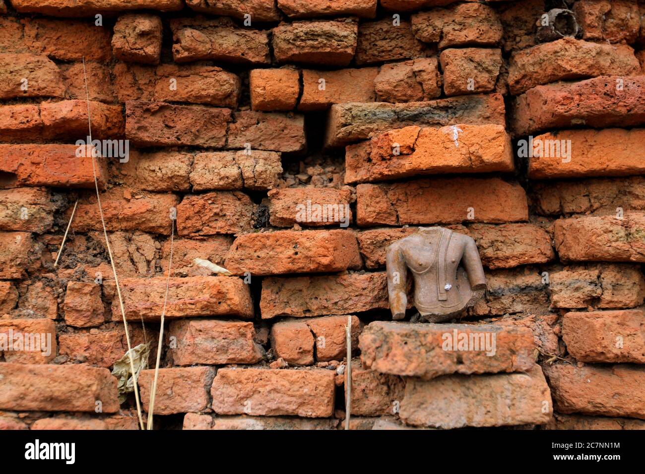 Uneven wall made of bricks and a broken sculpture resembling human ...