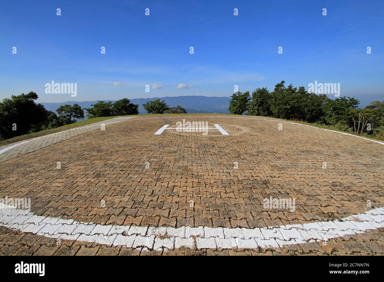 Empty helipad surrounded with grass and trees with clear sky visible on ...
