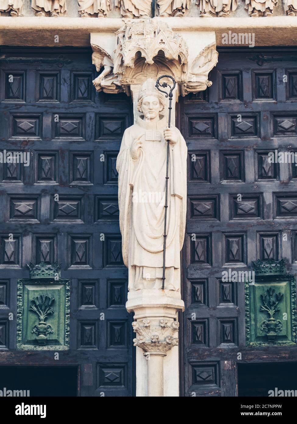Vertical shot of statues of a human figure on an exterior wall of a ...